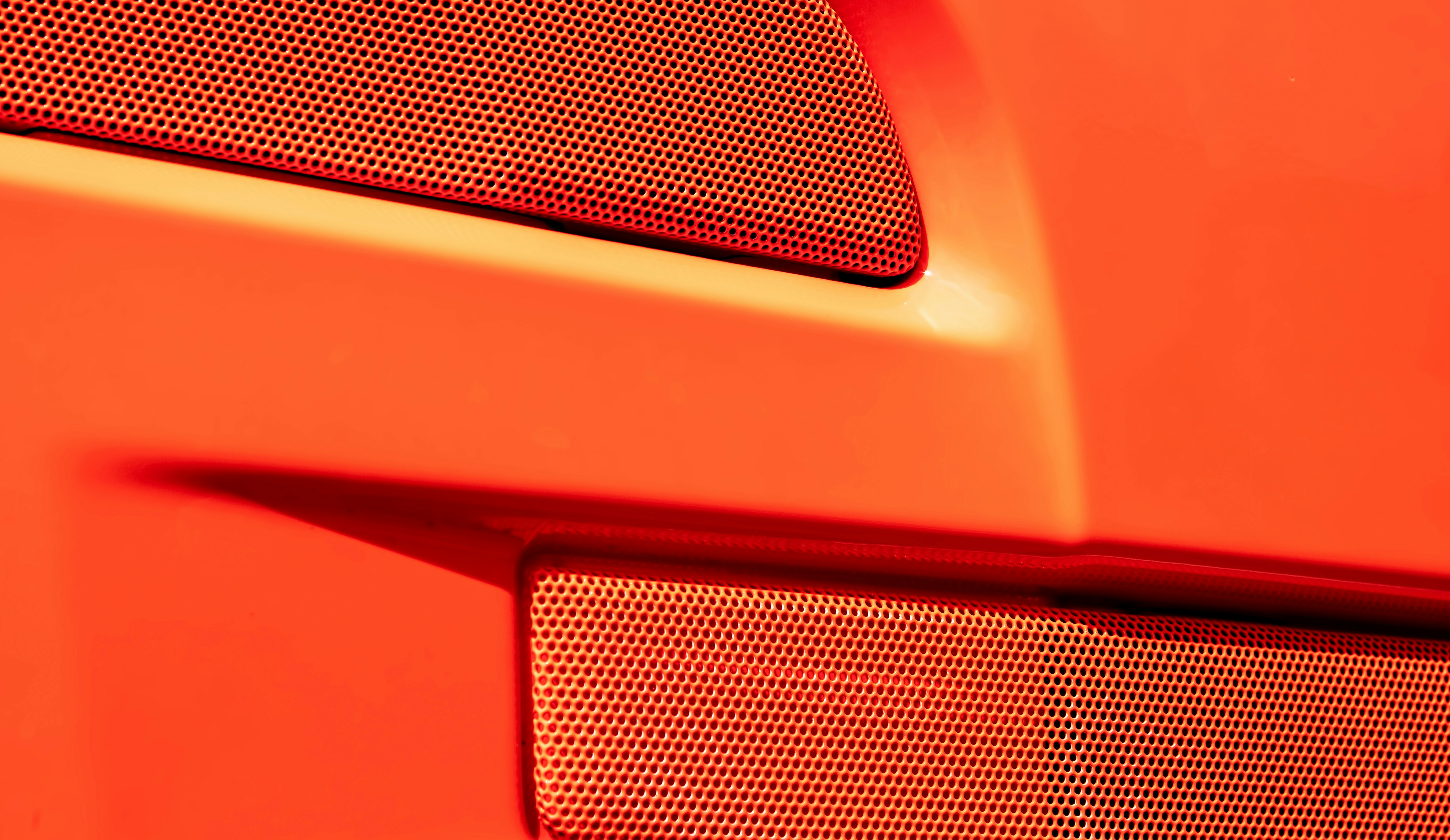 Close-up of a textured surface featuring mesh patterns and bold orange colors, emphasizing the intricacies of automotive design.
