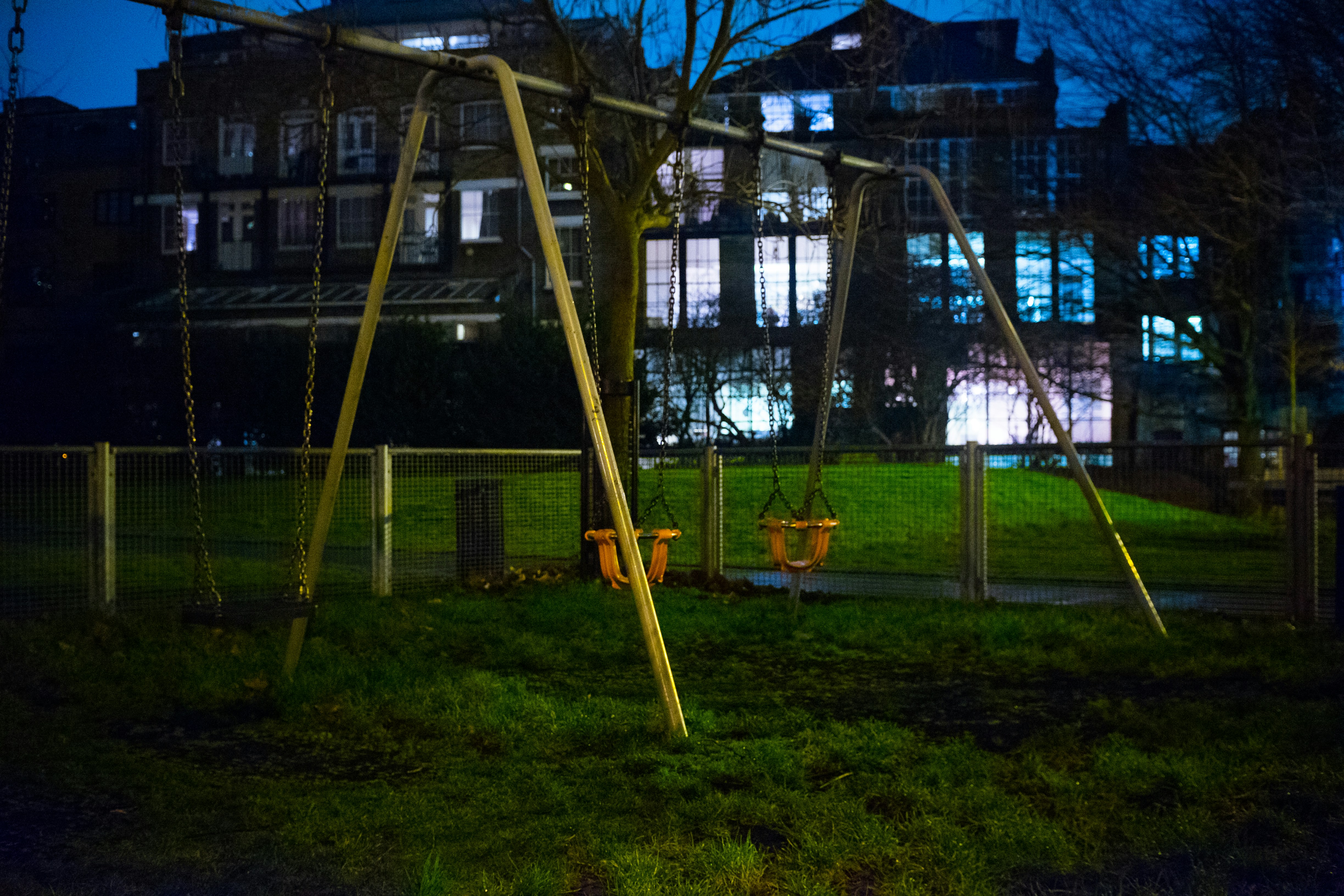 Blue Hour Swing Set Under Neon-Washed Windows