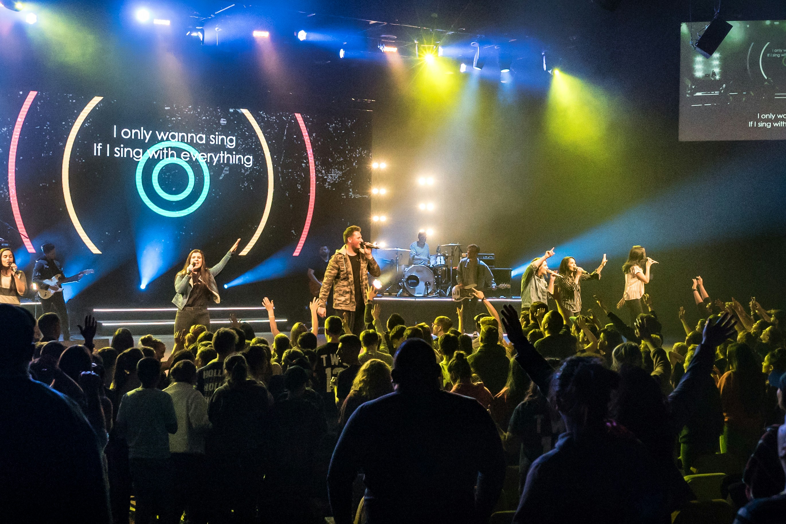 Lead Vocalist Under Concentric Neon Rings as the Crowd Rises