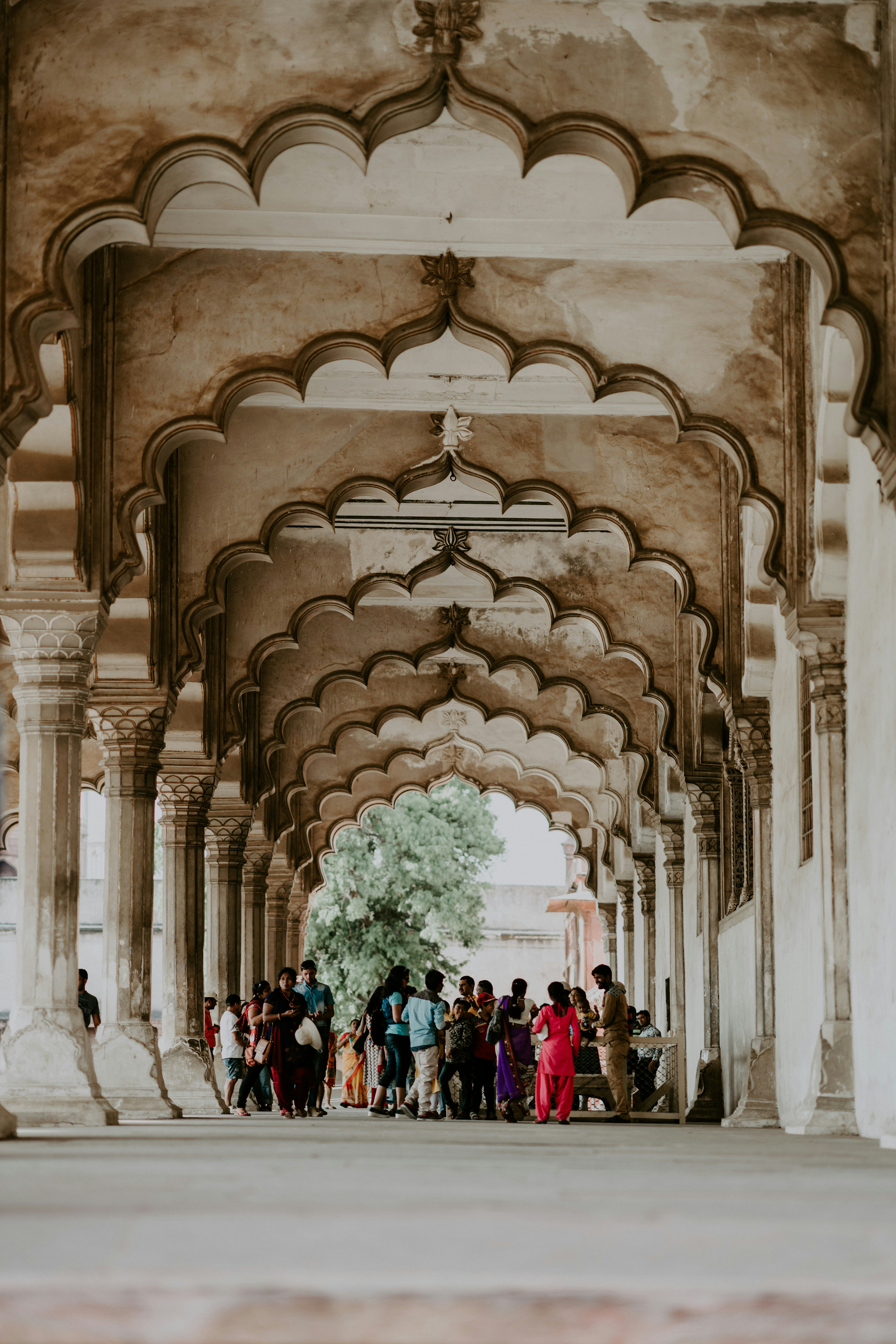 A vibrant crowd congregates beneath intricately arched columns, showcasing a blend of culture and architecture. The scene captures the essence of community in a historic setting.