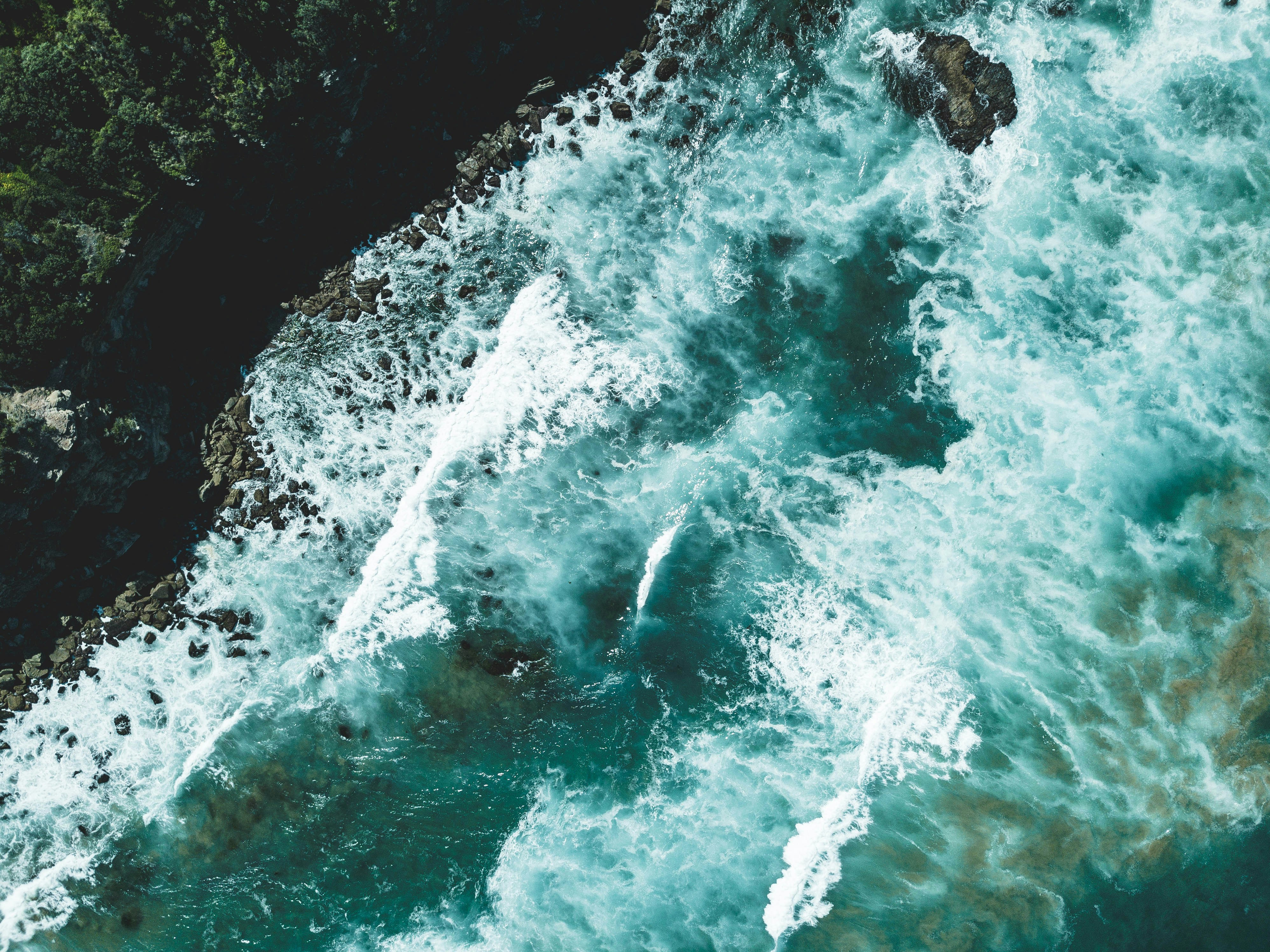 Aerial view of ocean waves crashing against a rocky coastline.
