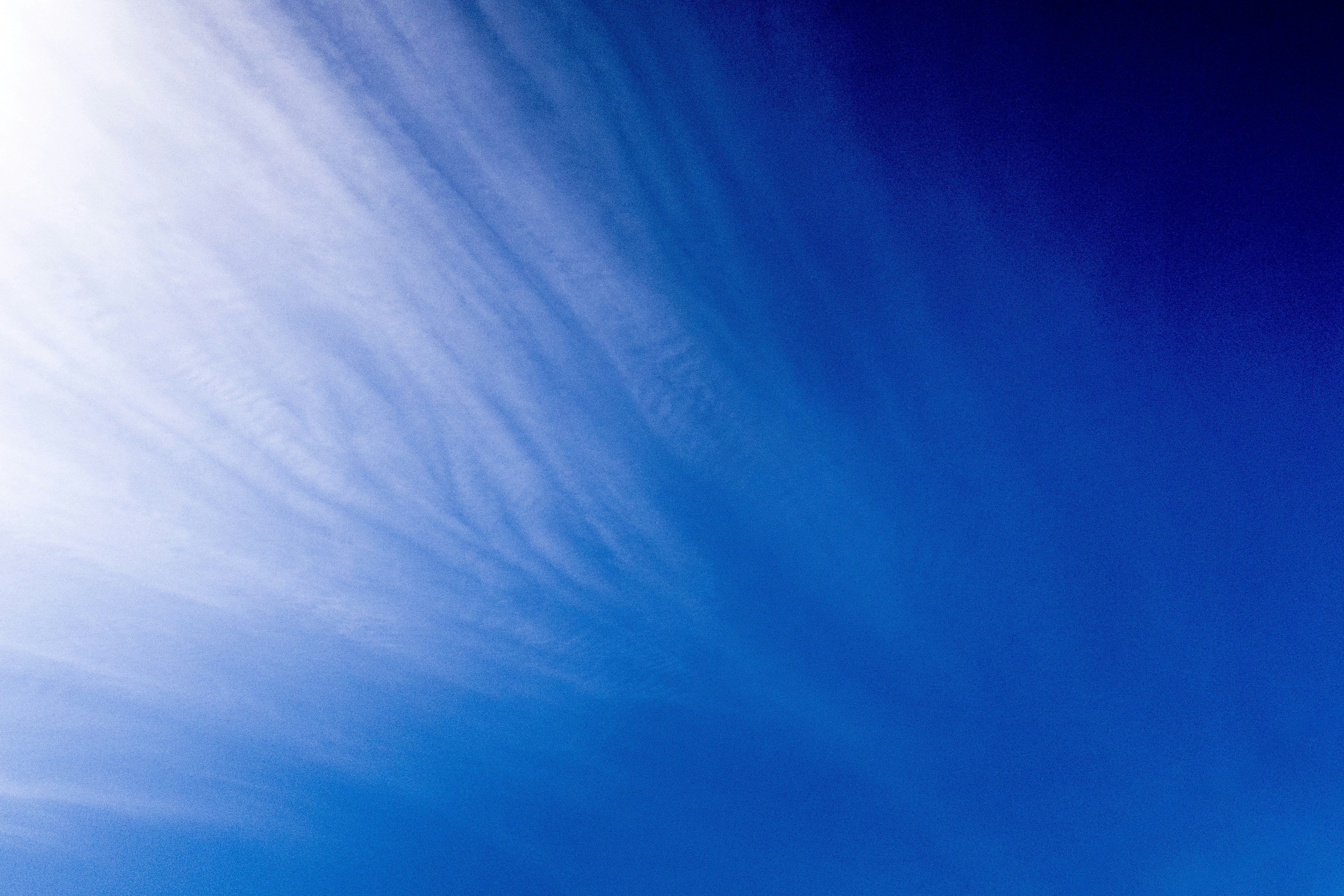 Soft, wispy clouds stretch across a deep blue sky, creating a serene and tranquil atmosphere.