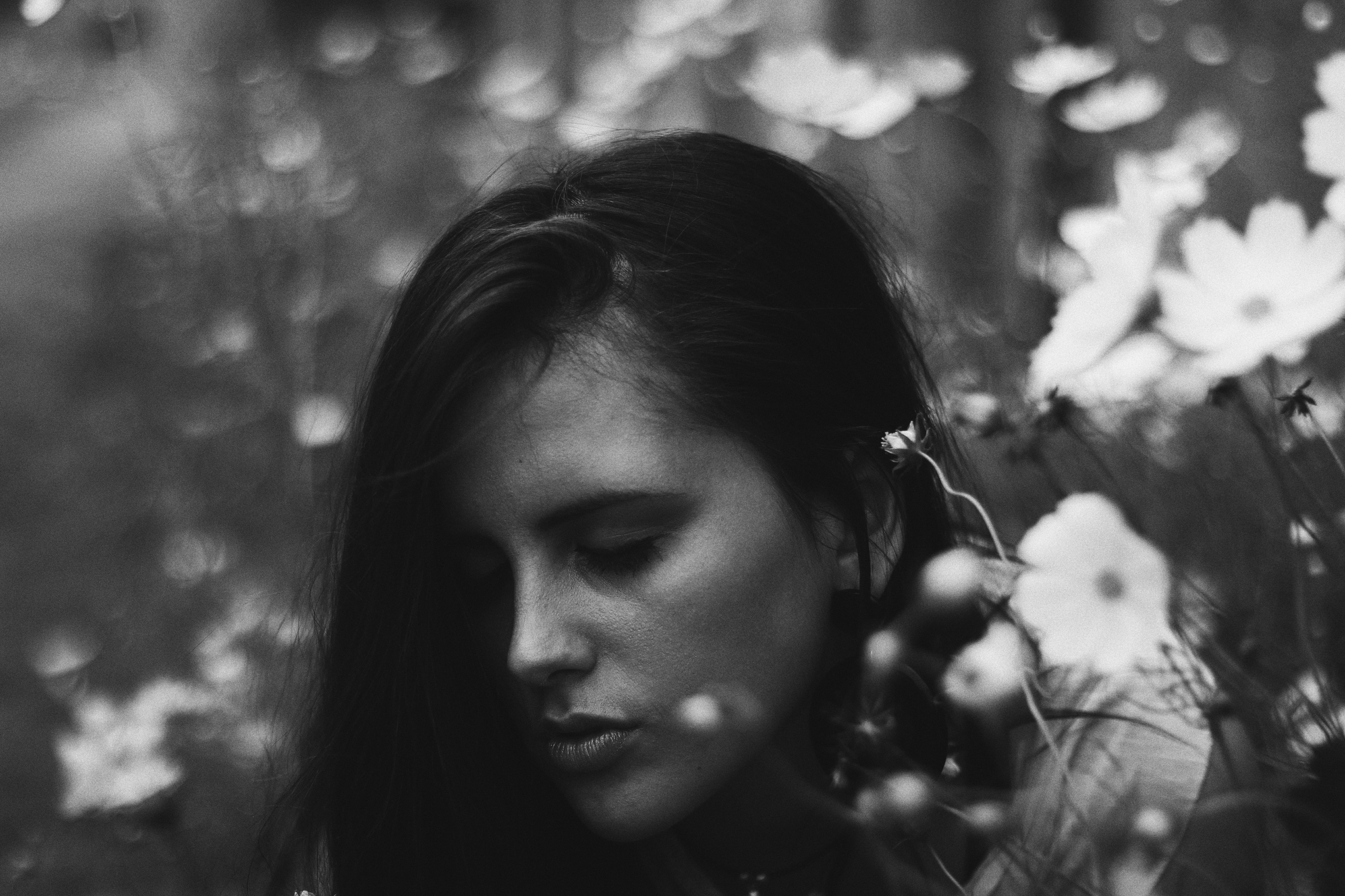 Grayscale portrait of a woman surrounded by wildflowers, conveying serene introspection.