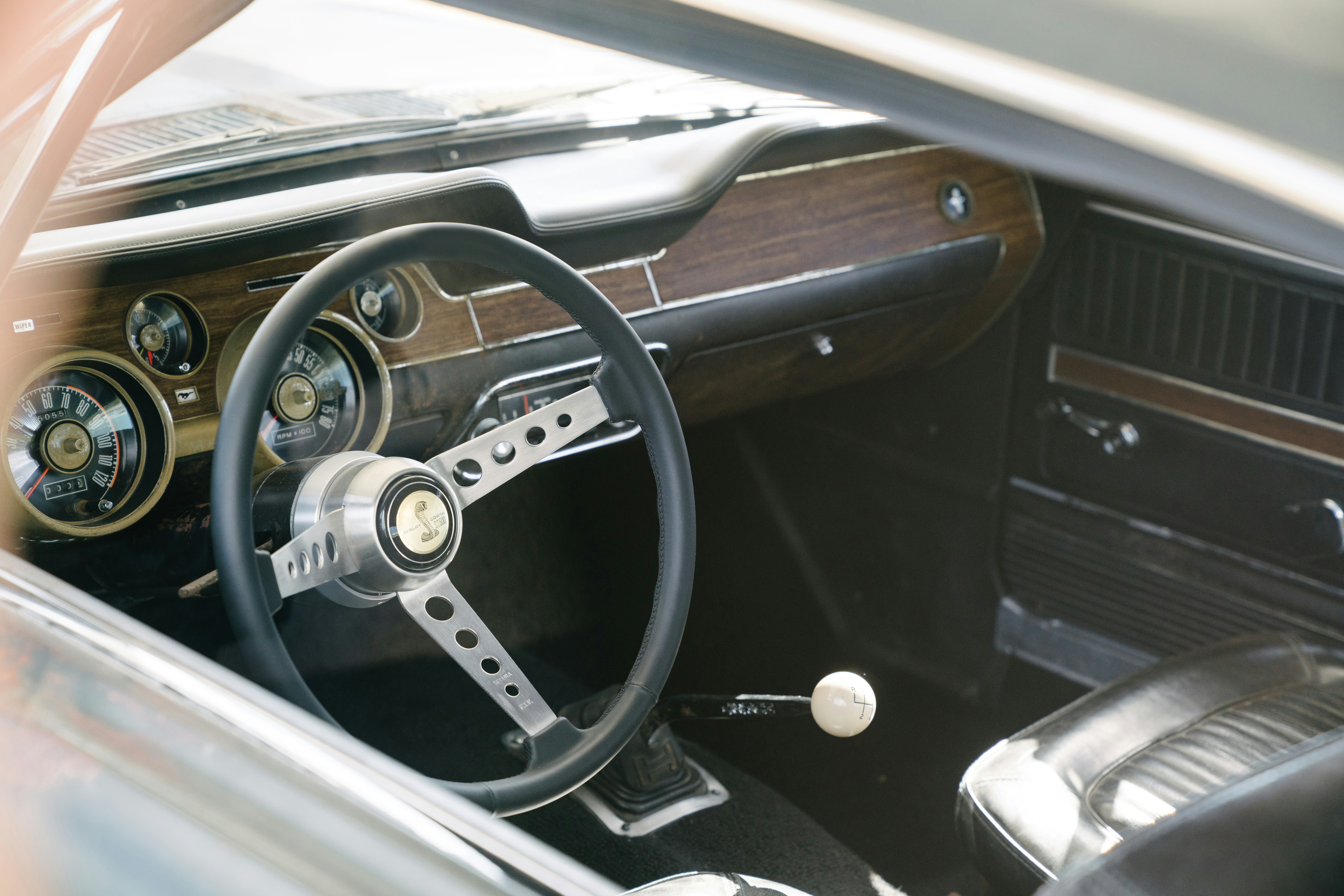 Classic car dashboard with wooden accents and vintage steering wheel.