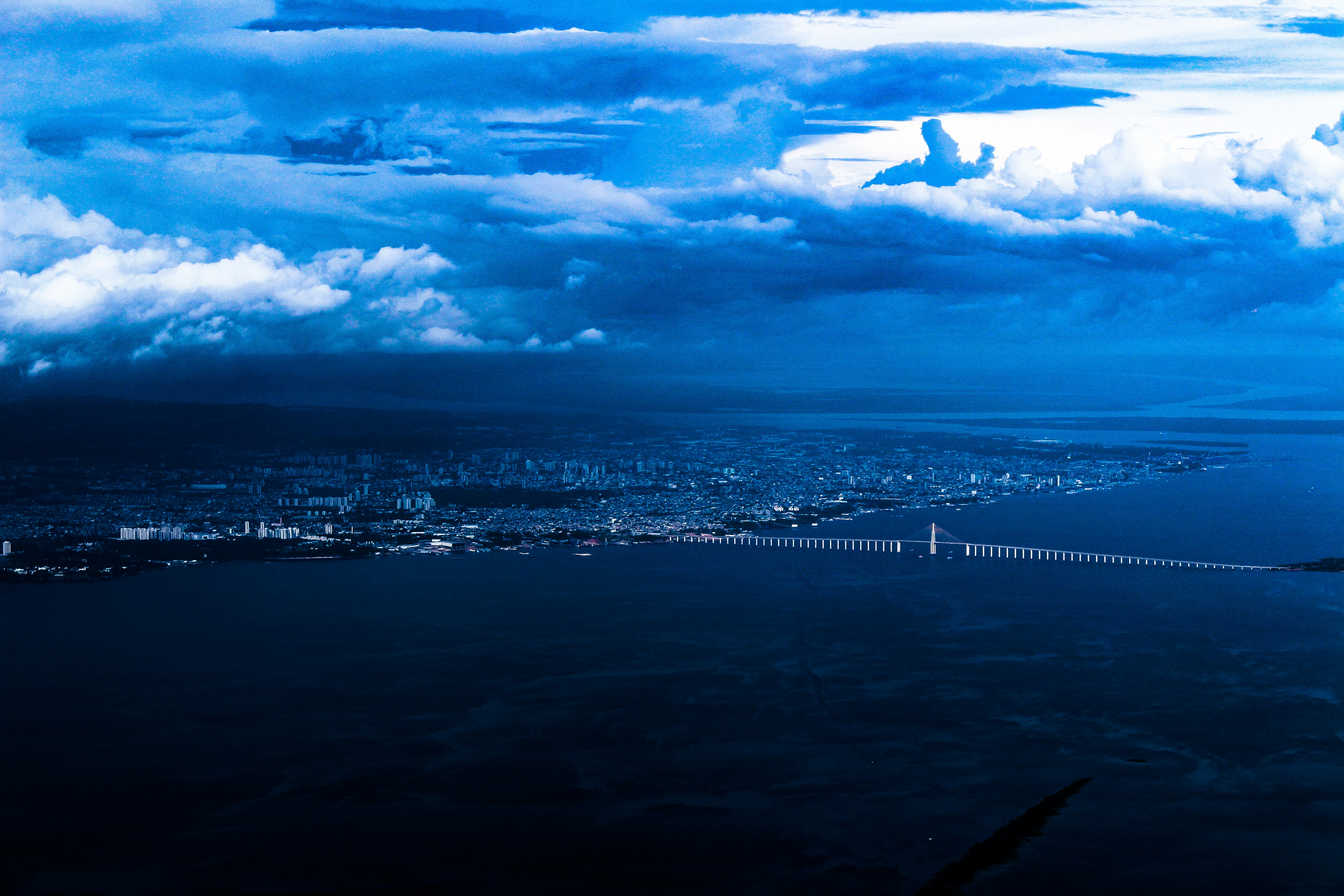 Aerial view of Manaus cityscape with dramatic cloud formations and expansive waterway.