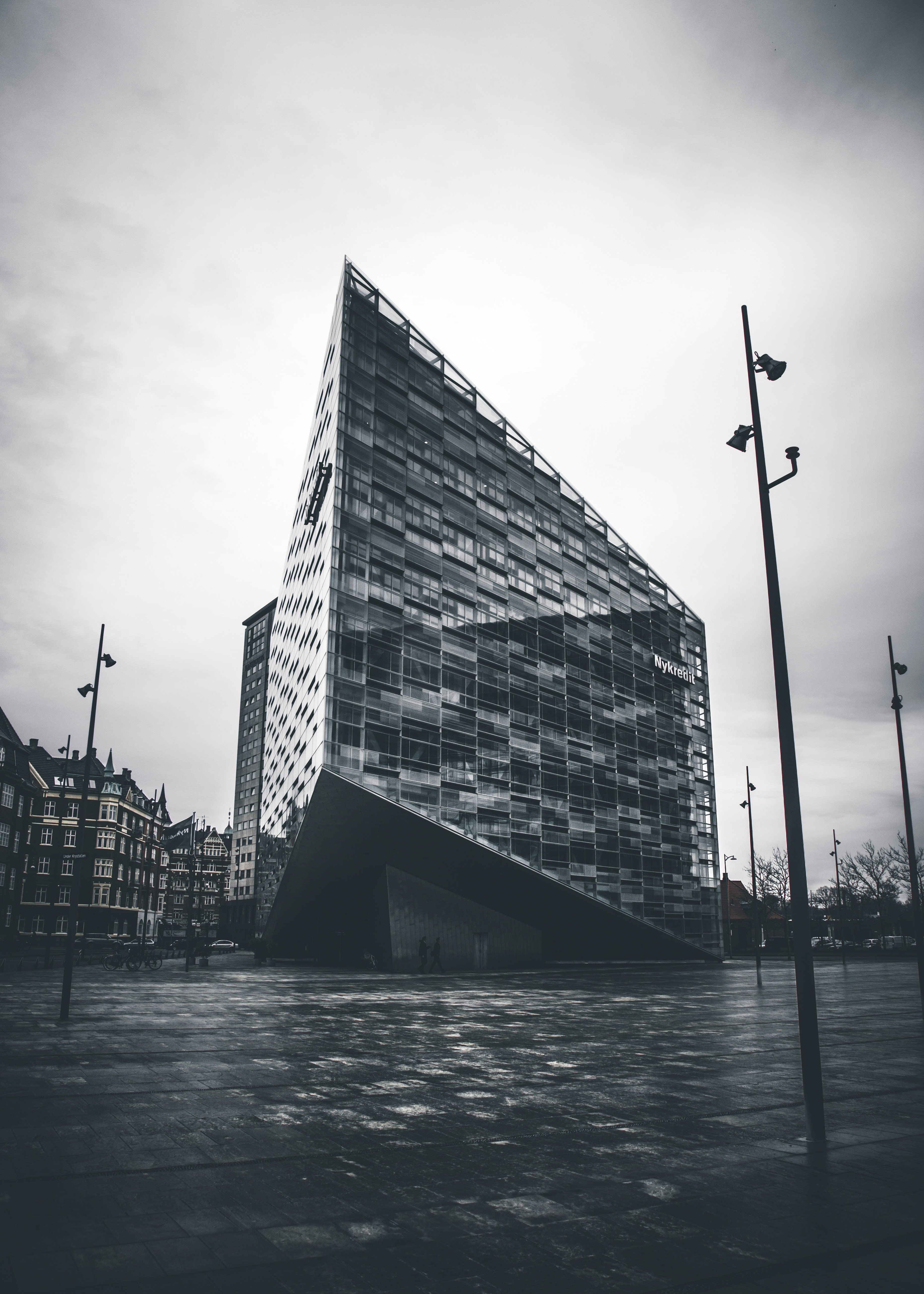 A striking modern architectural design featuring a glass facade and angular shapes, set against a cloudy sky.