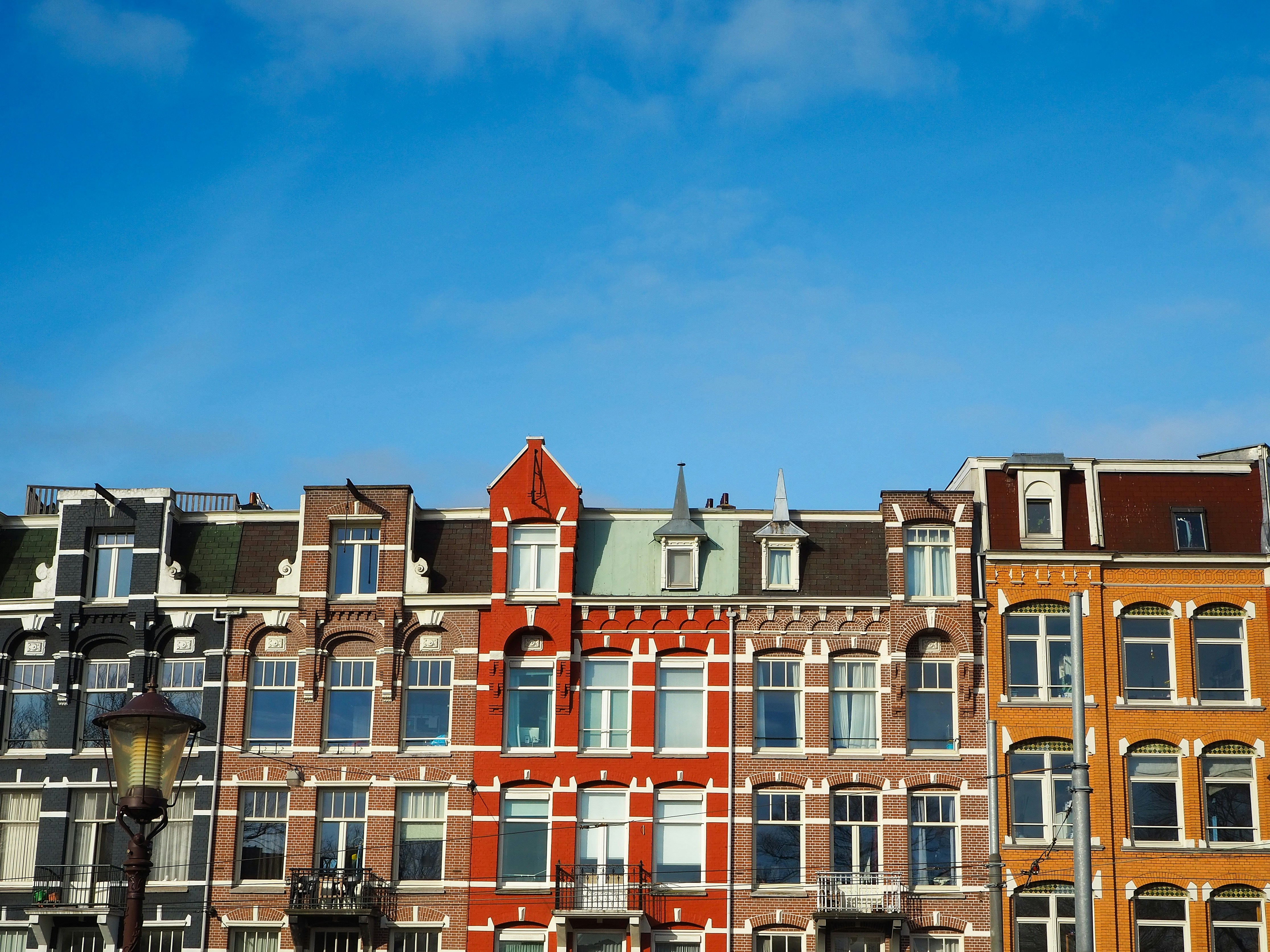 Colorful historic buildings line the Nassaukade against a vivid blue sky.