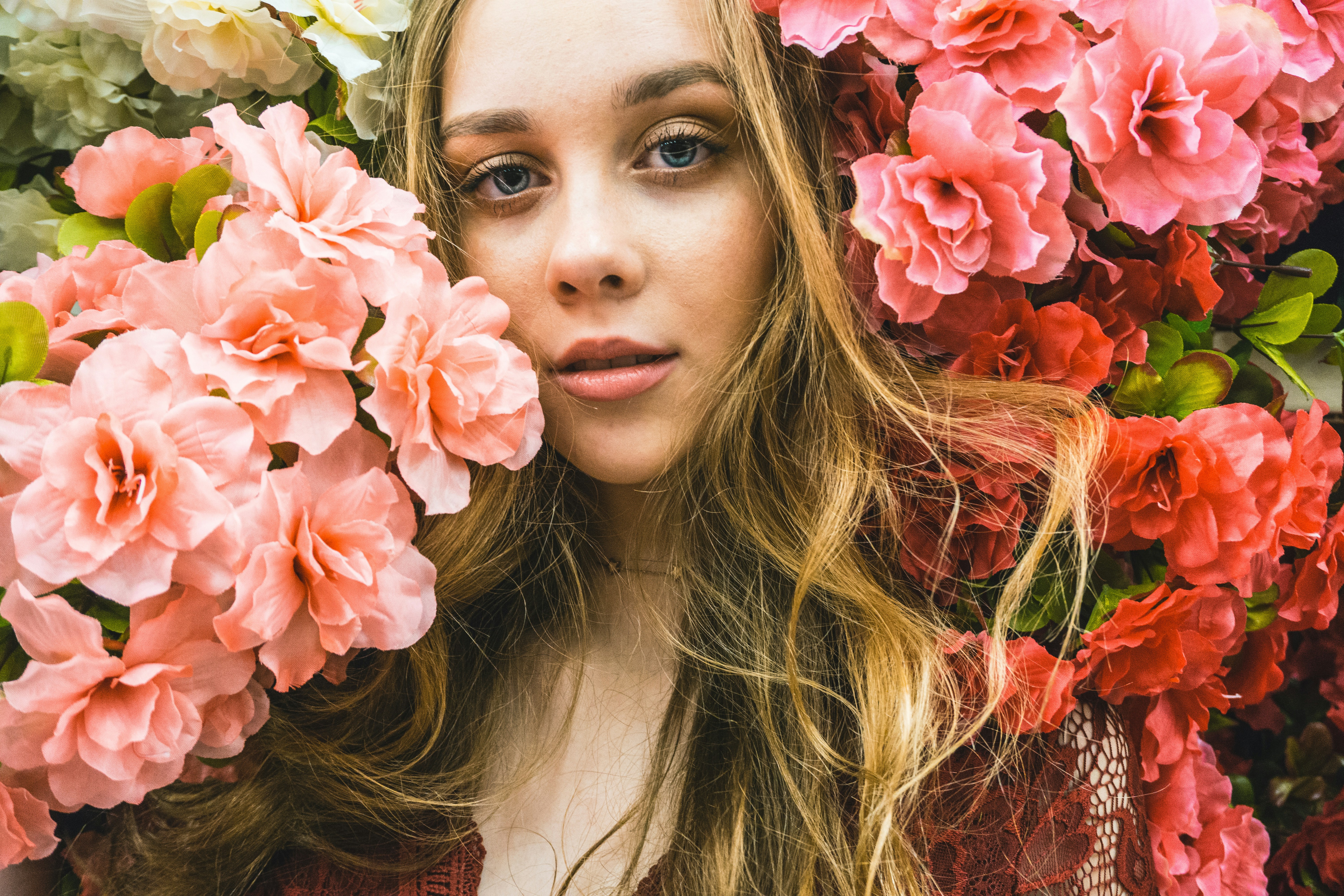 Young woman surrounded by vibrant pink flowers, showcasing a harmonious blend of nature and beauty.