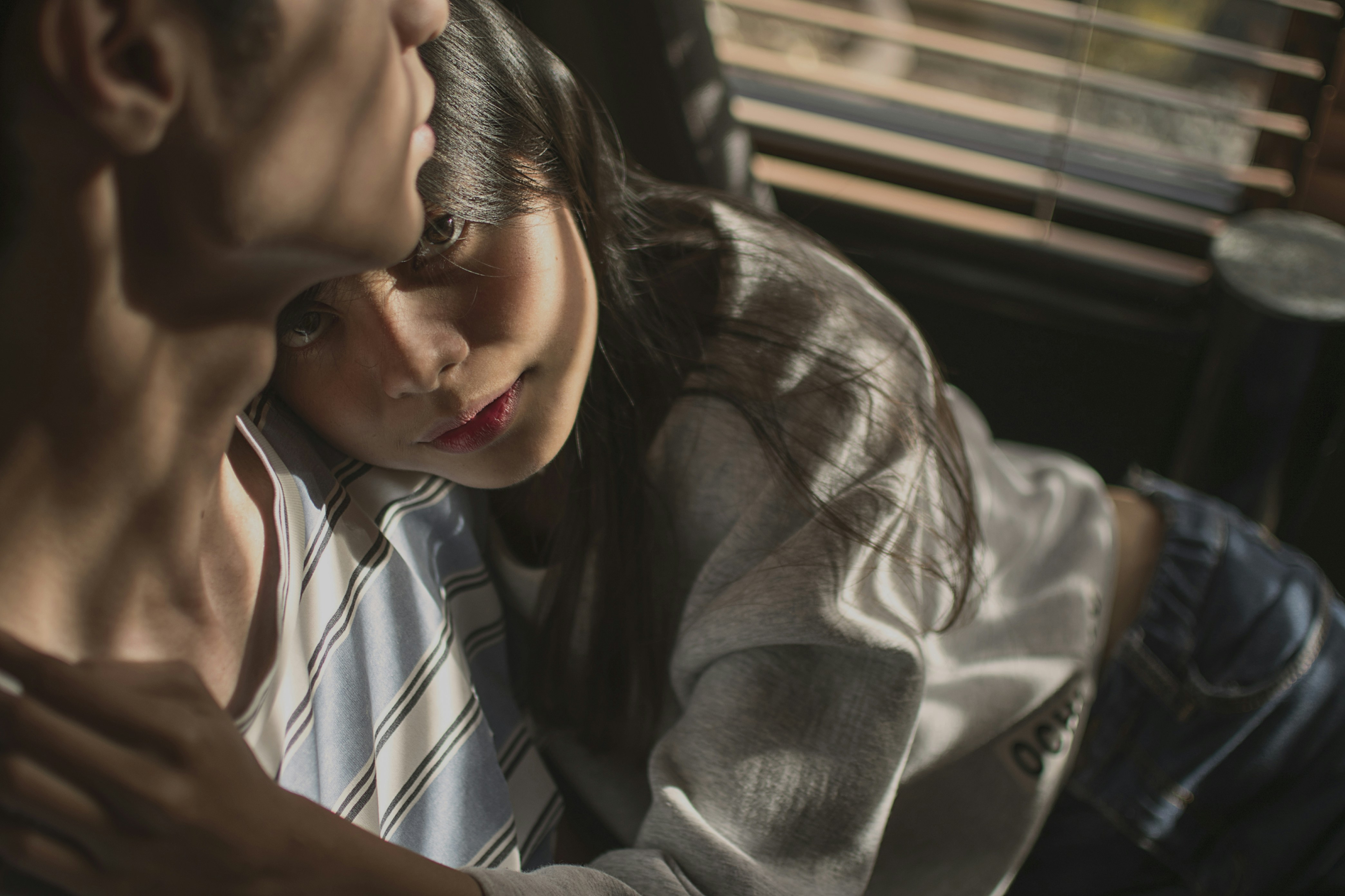 Woman resting her head on a man's shoulder in a softly lit room.