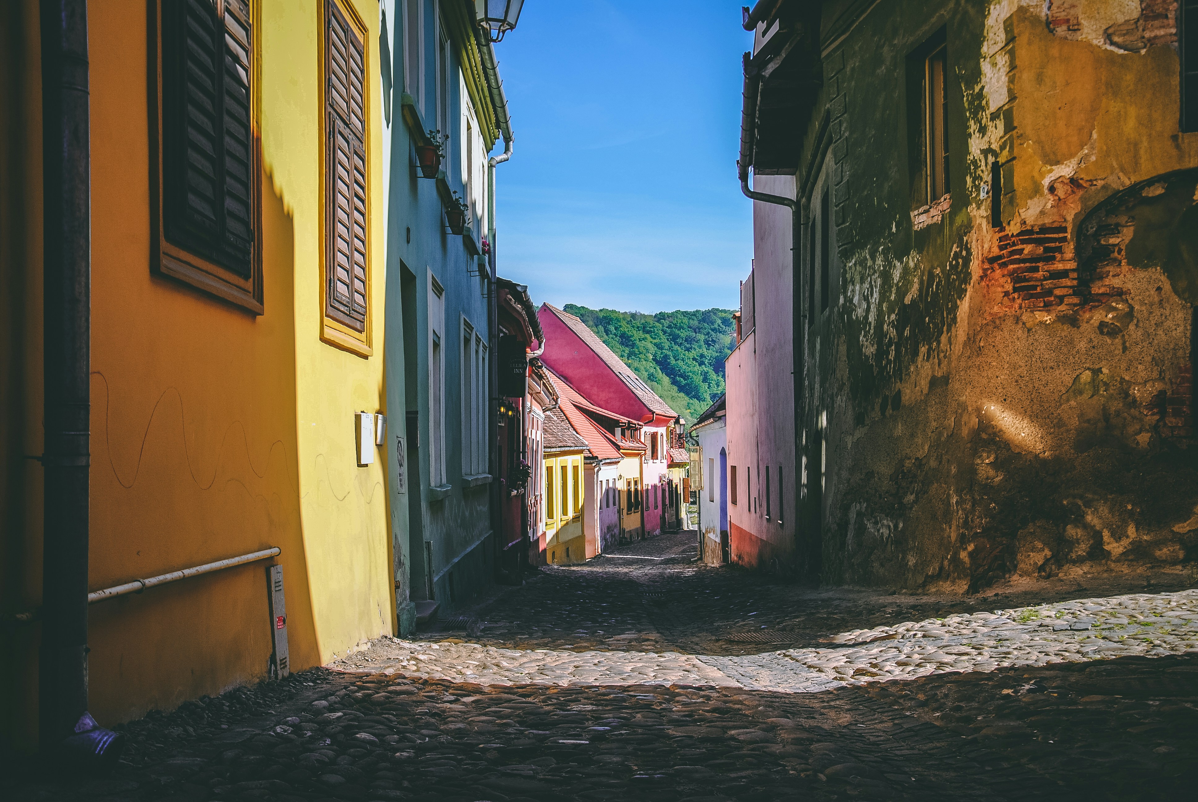 Narrow cobblestone street flanked by vibrant, multicolored buildings under a clear blue sky.