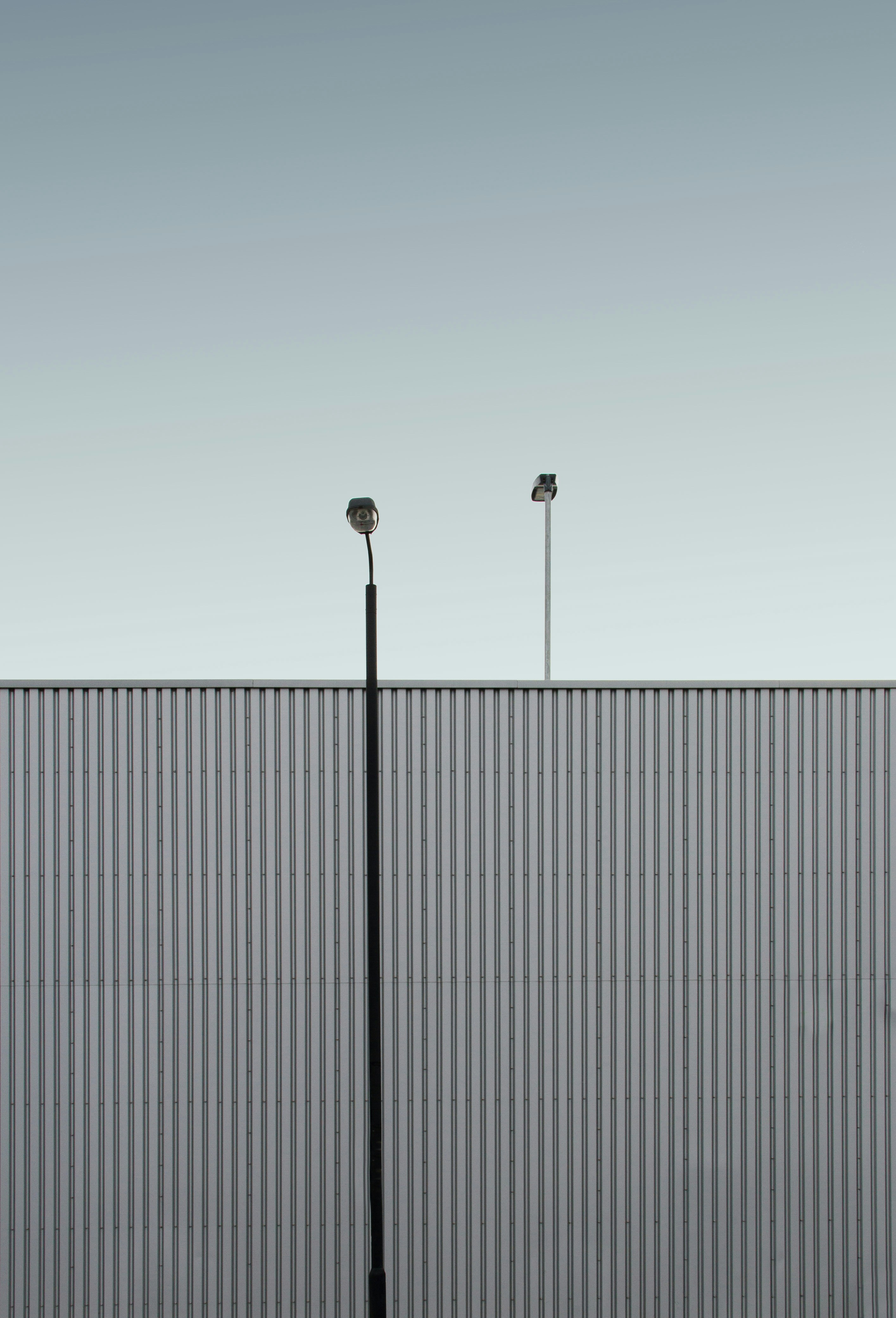 Solitary Lantern Over a Pleated Wall Under a Blue Gradient Sky