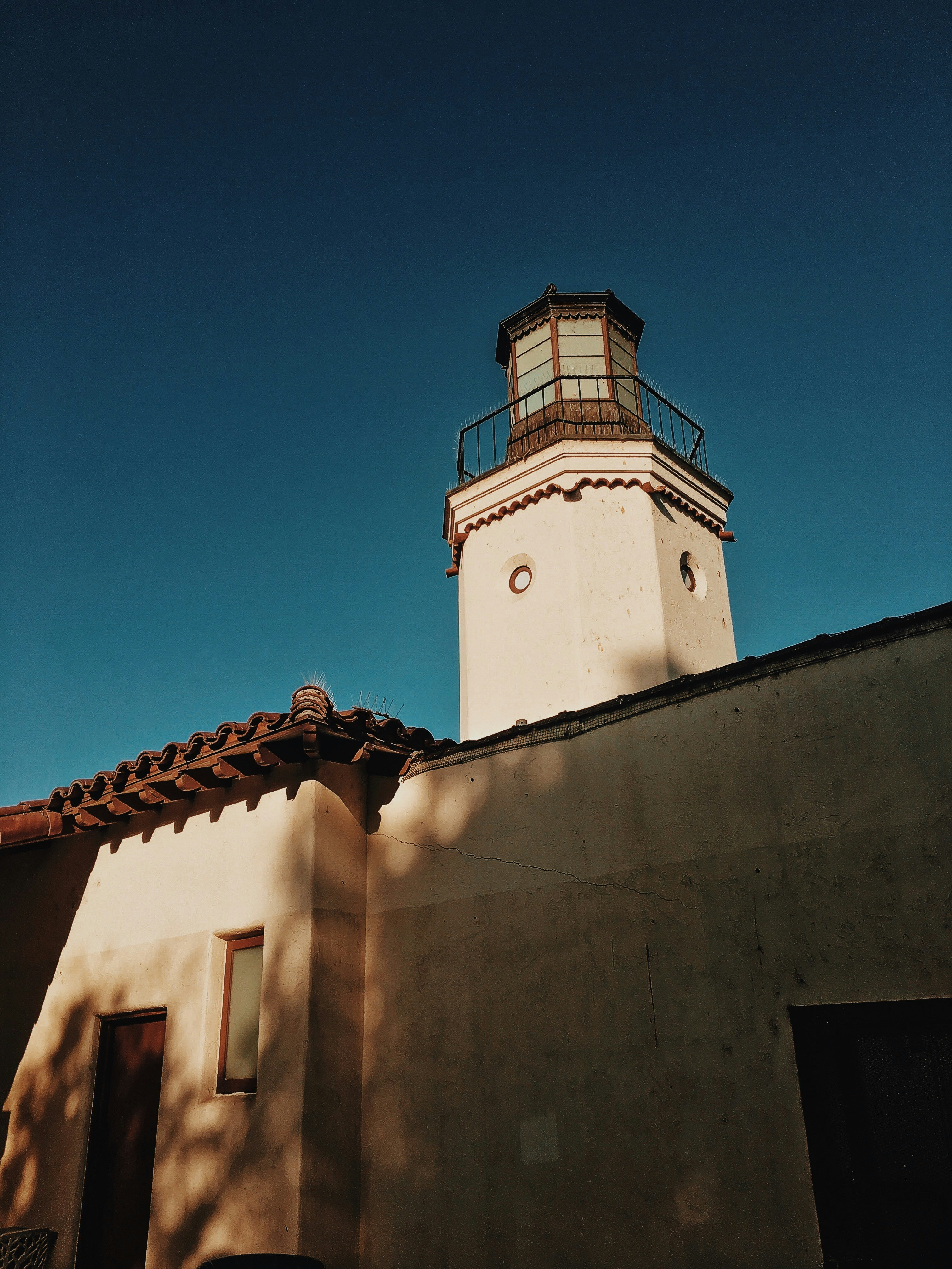 Classic lighthouse standing tall against a clear blue sky, with architectural details showcasing its historical significance.