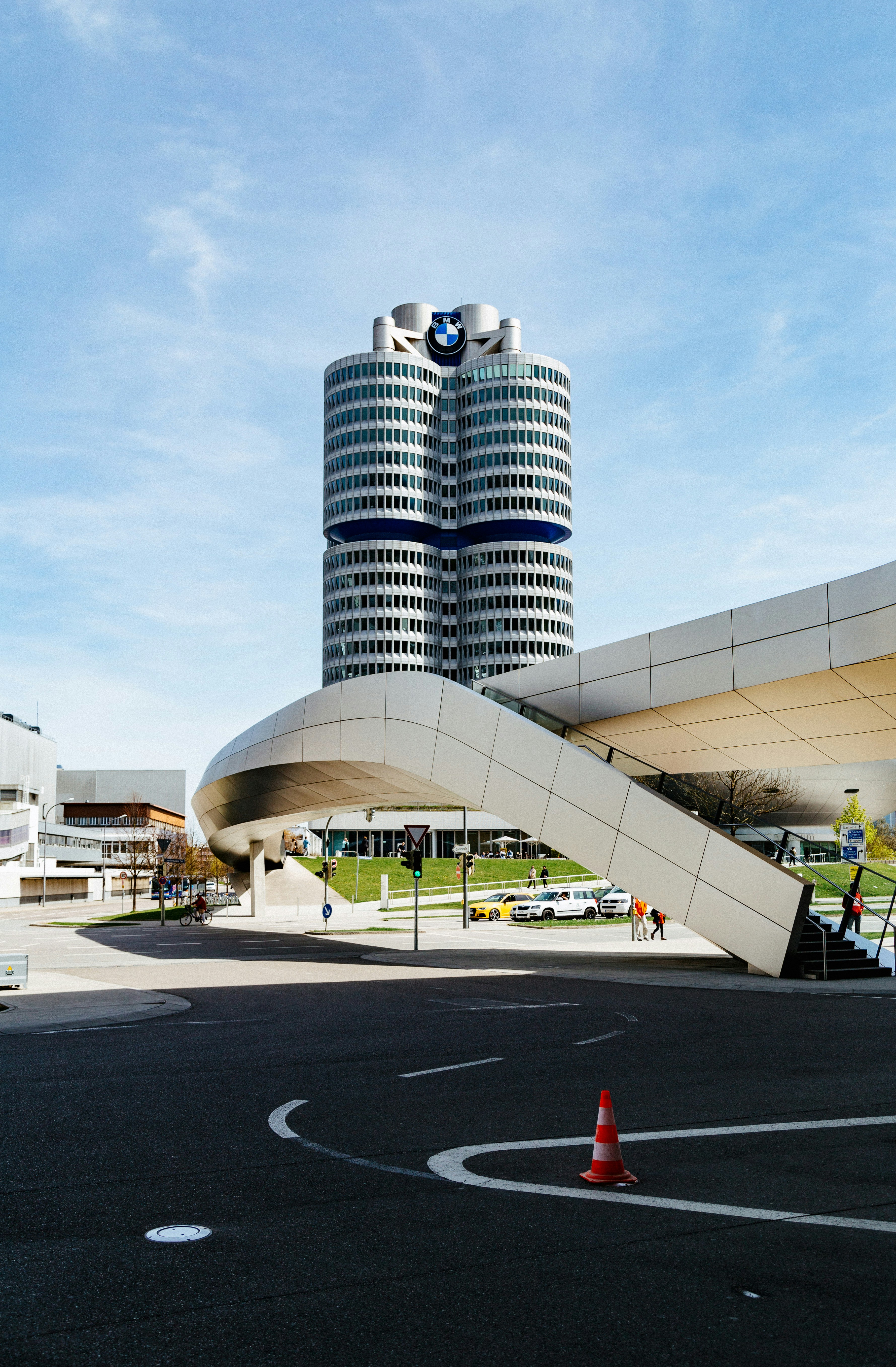 Modern BMW headquarters with a unique curved walkway and dynamic architectural lines, set against a clear blue sky.