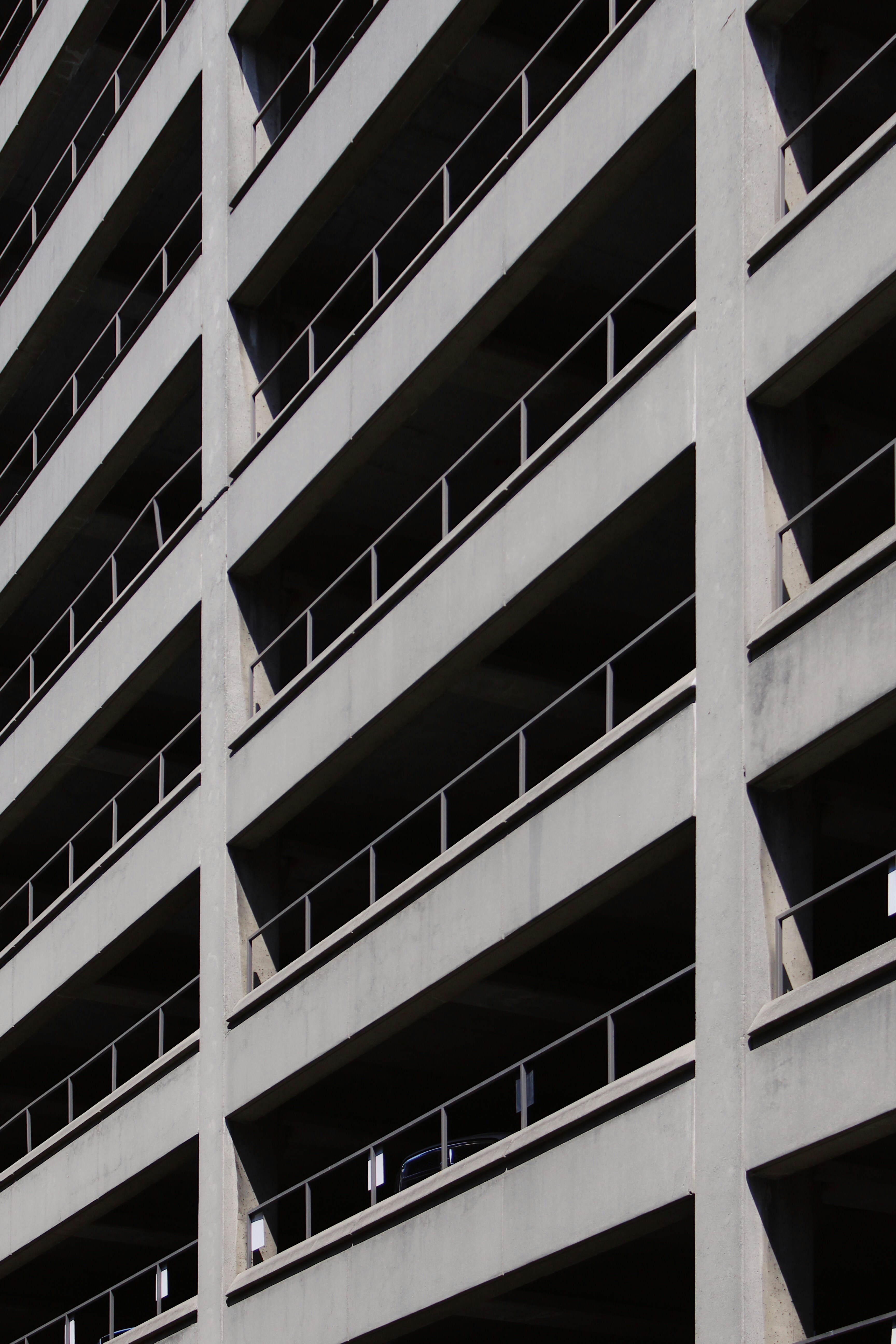 Vertical concrete structure showcasing a series of parallel lines and balconies. The architectural design emphasizes minimalism and urban functionality.