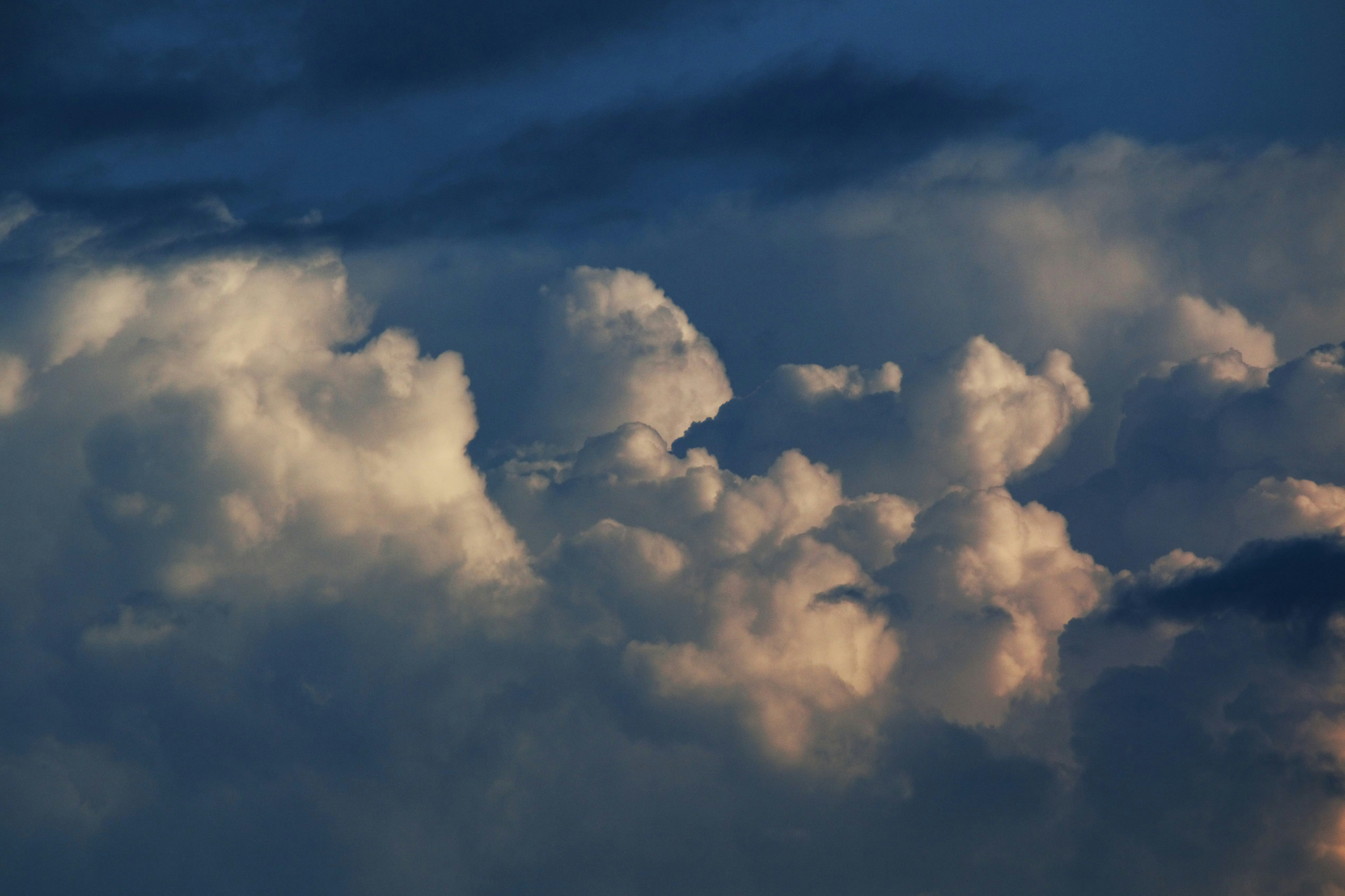 Fluffy clouds illuminated by soft light, creating a serene atmosphere against a deep blue backdrop.