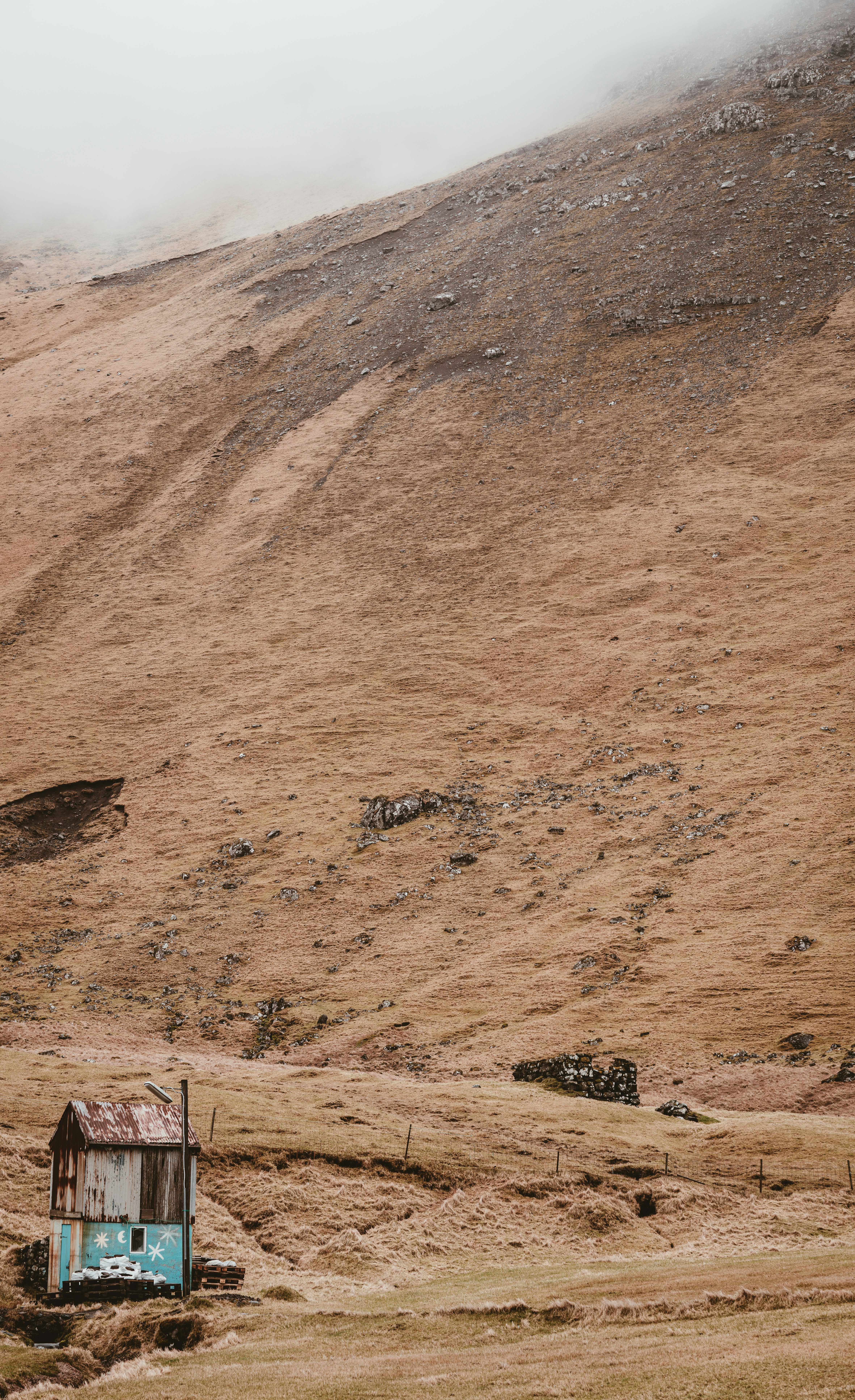 Rusted Shelter Beneath a Misty Slope