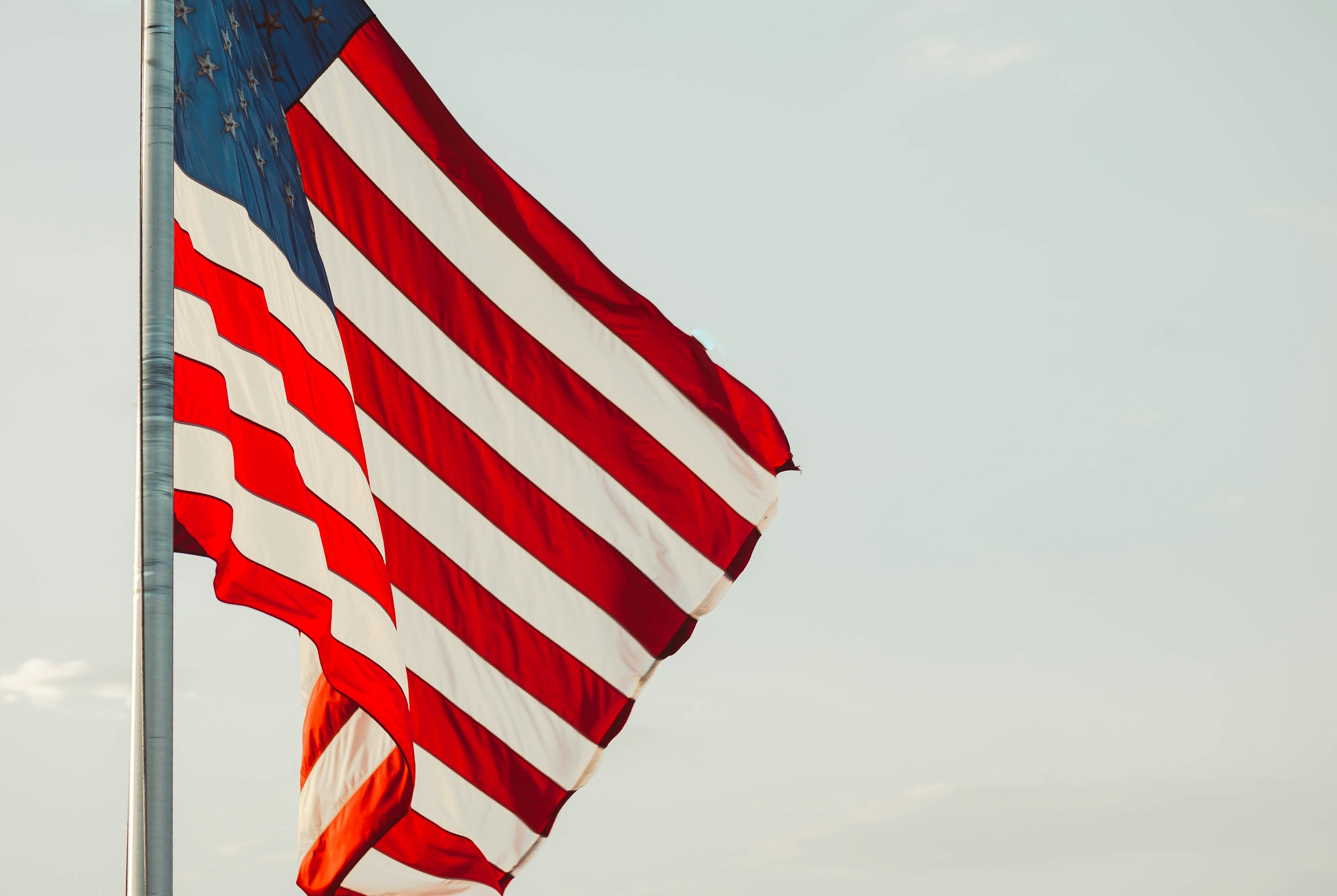 American flag billowing against a clear sky.