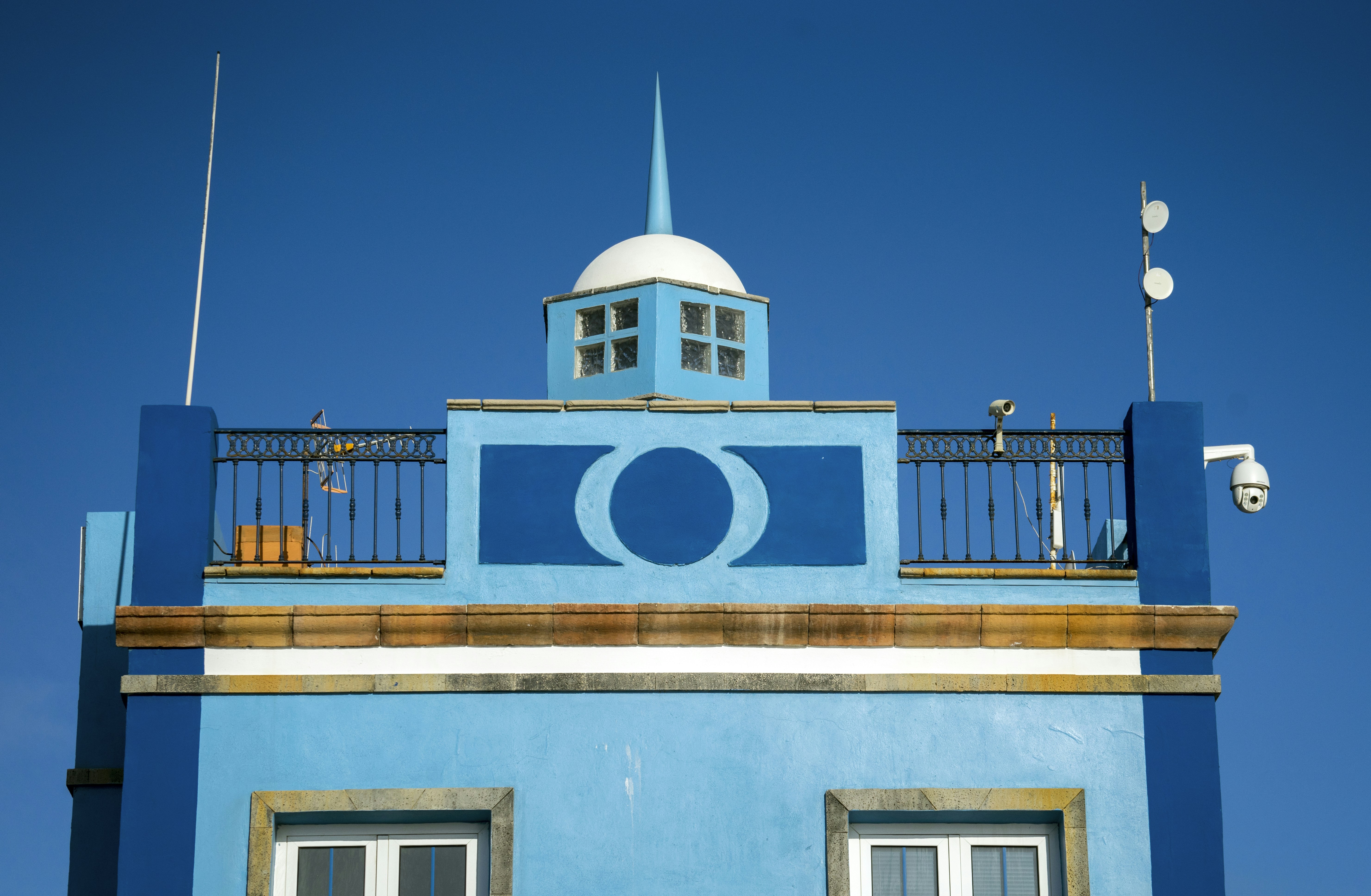 Azure Crest: Crescent Emblem on a Sunlit Blue Rooftop