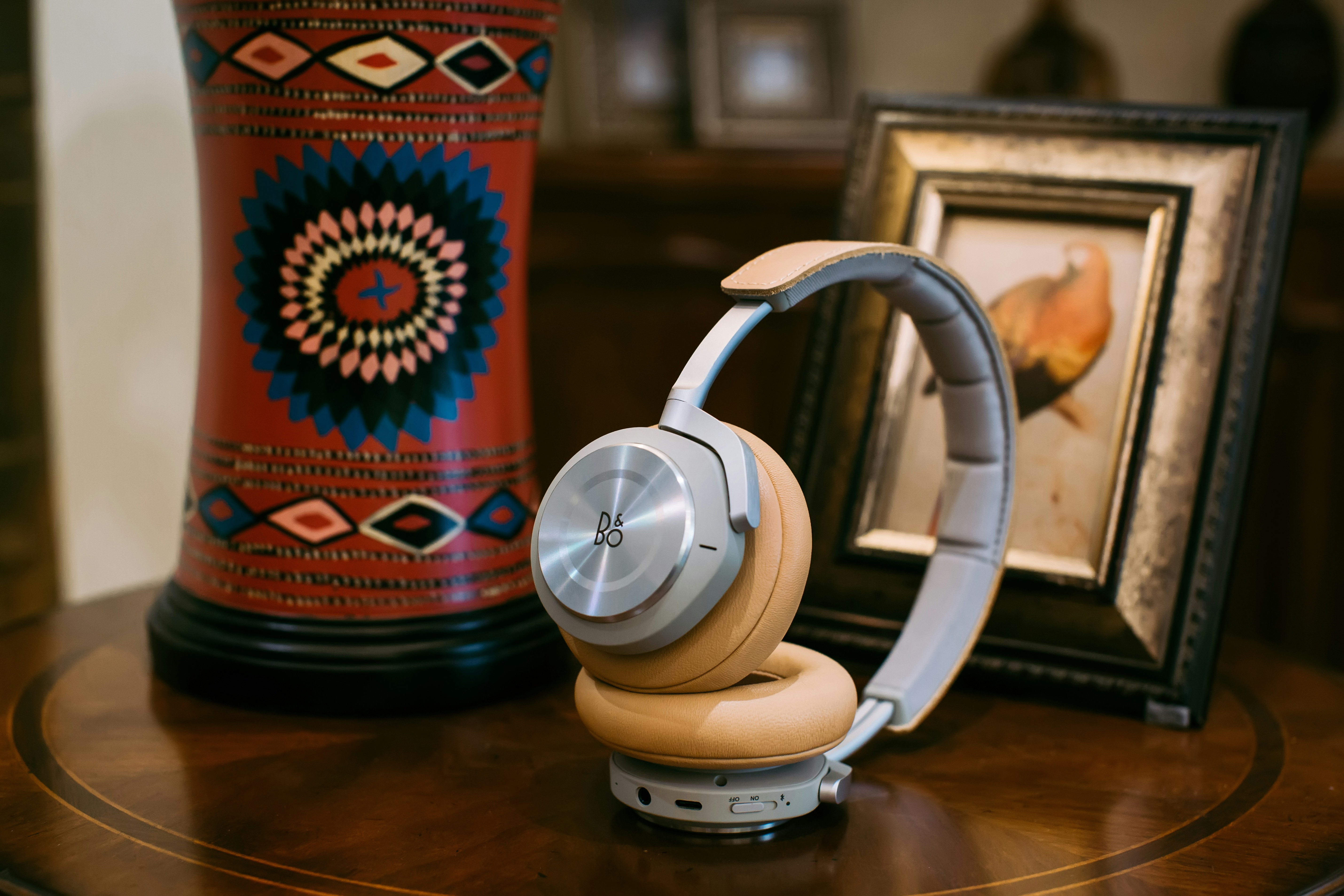 Silver and beige wireless headphones beside bird photo in frame photo ...