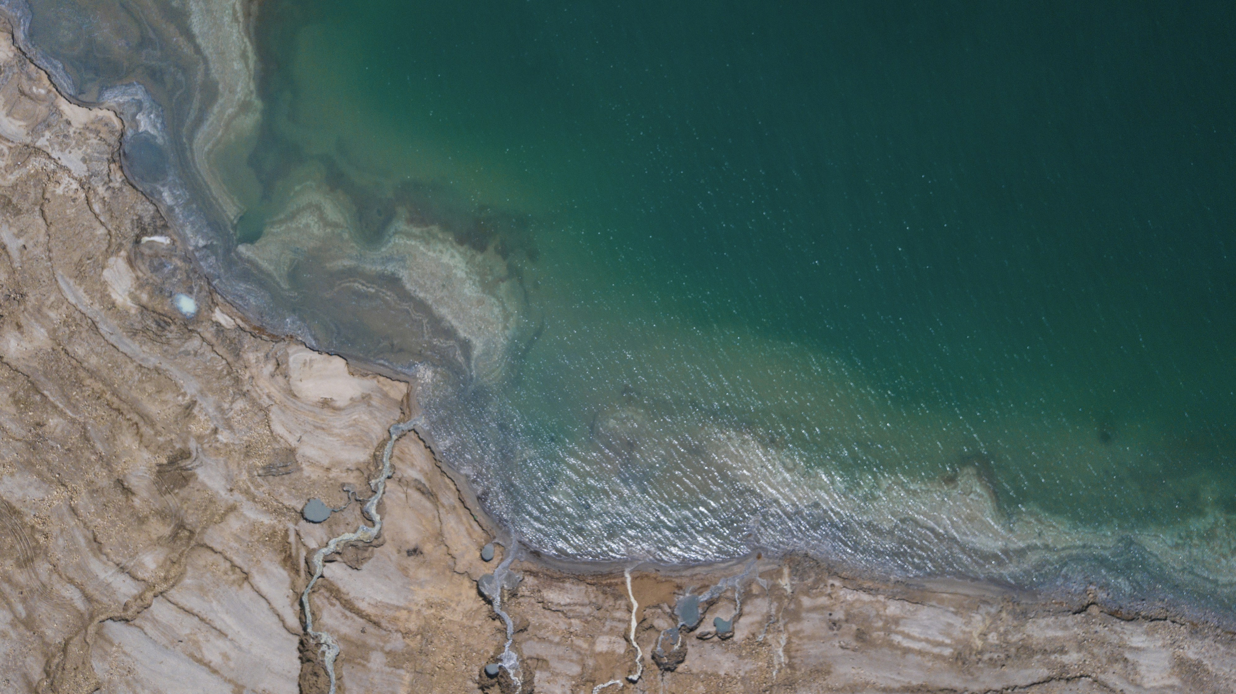 Coastal landscape with intricate rock formations meeting turquoise waters.