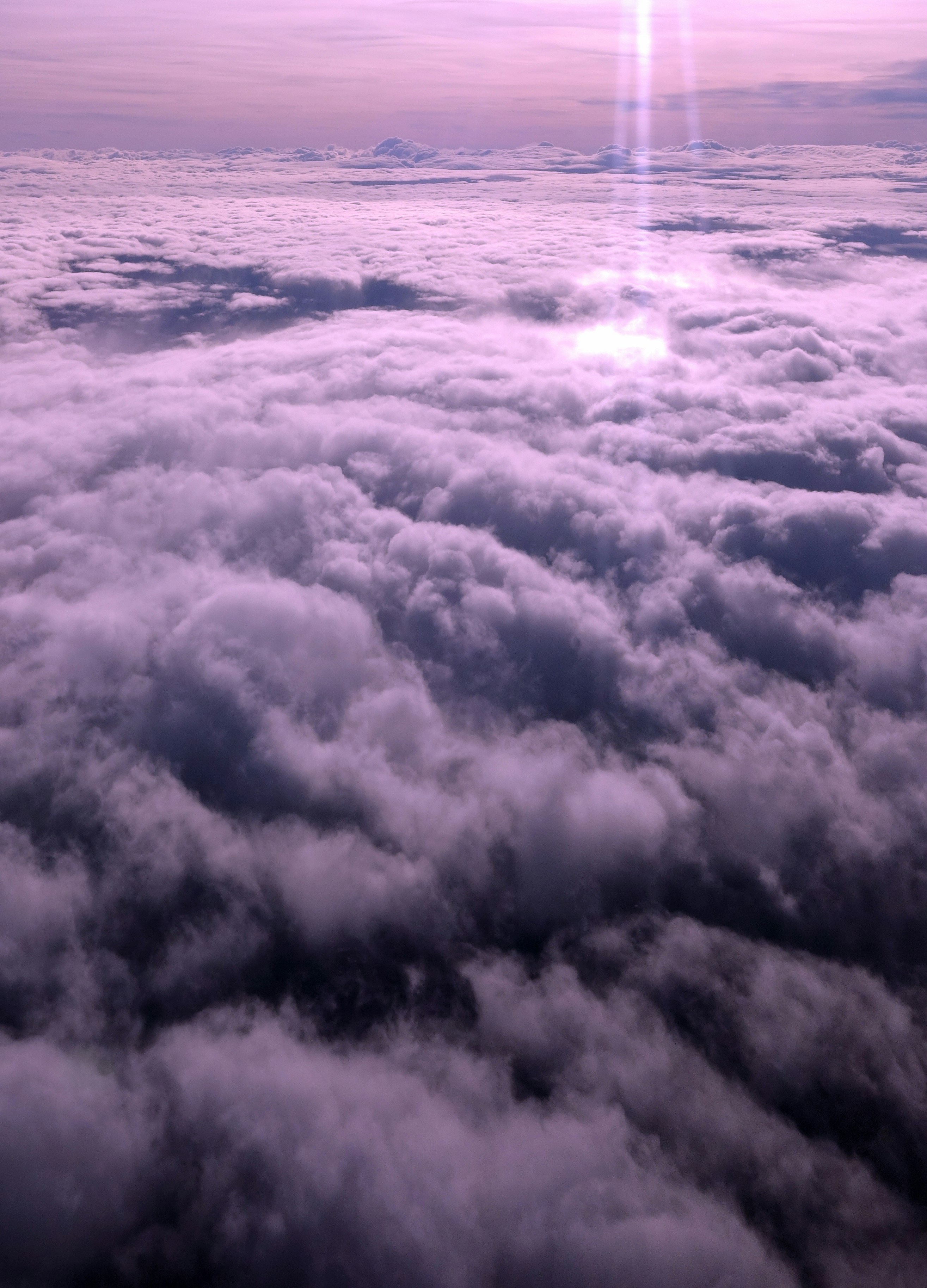 Soft purple hues blend with fluffy clouds, creating a serene aerial landscape at twilight.