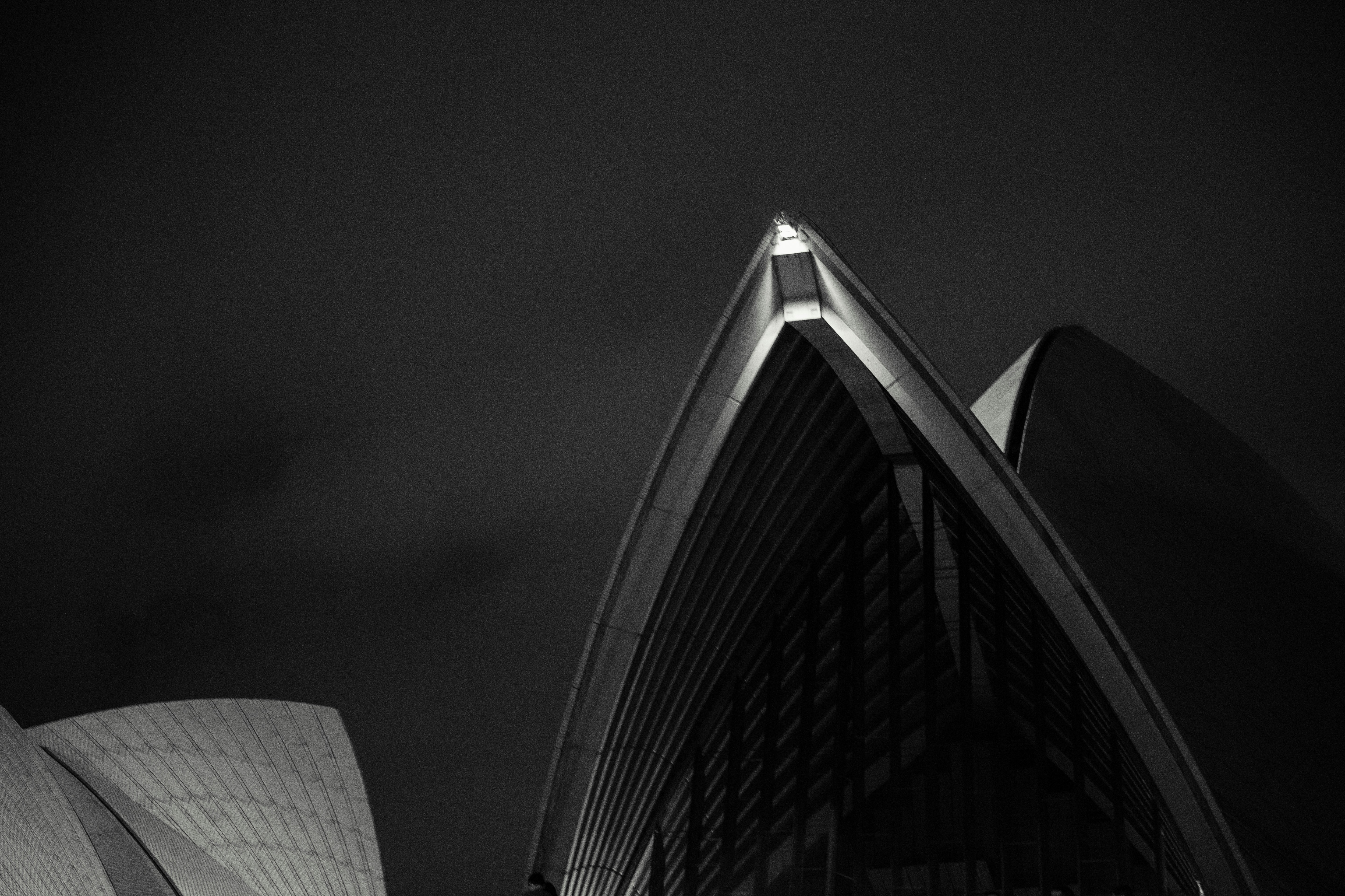 Dramatic angles of the Sydney Opera House illuminated against a night sky, showcasing its unique architectural design.