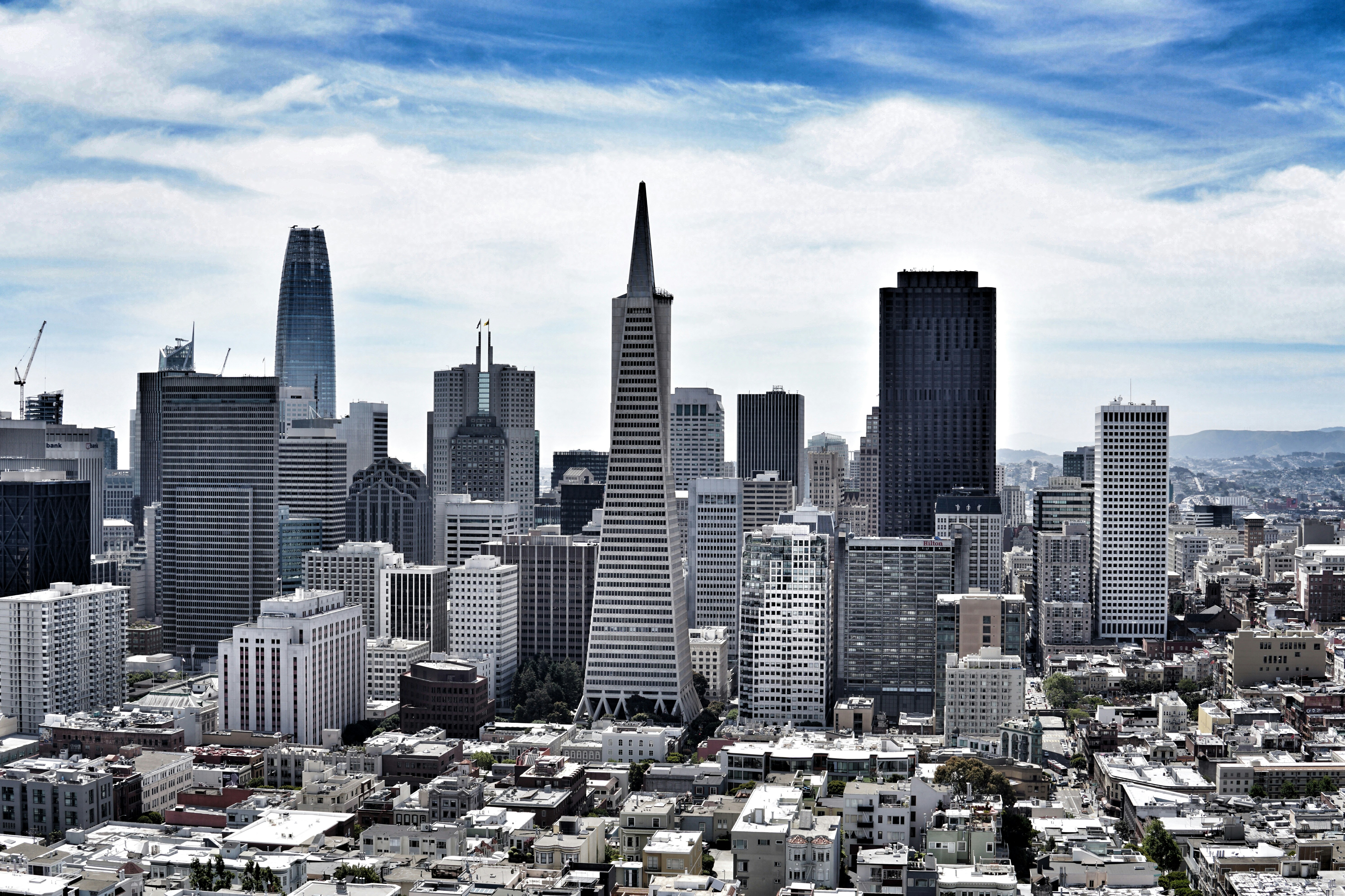 San Francisco skyline showcasing the Transamerica Pyramid and surrounding skyscrapers under a partly cloudy sky.
