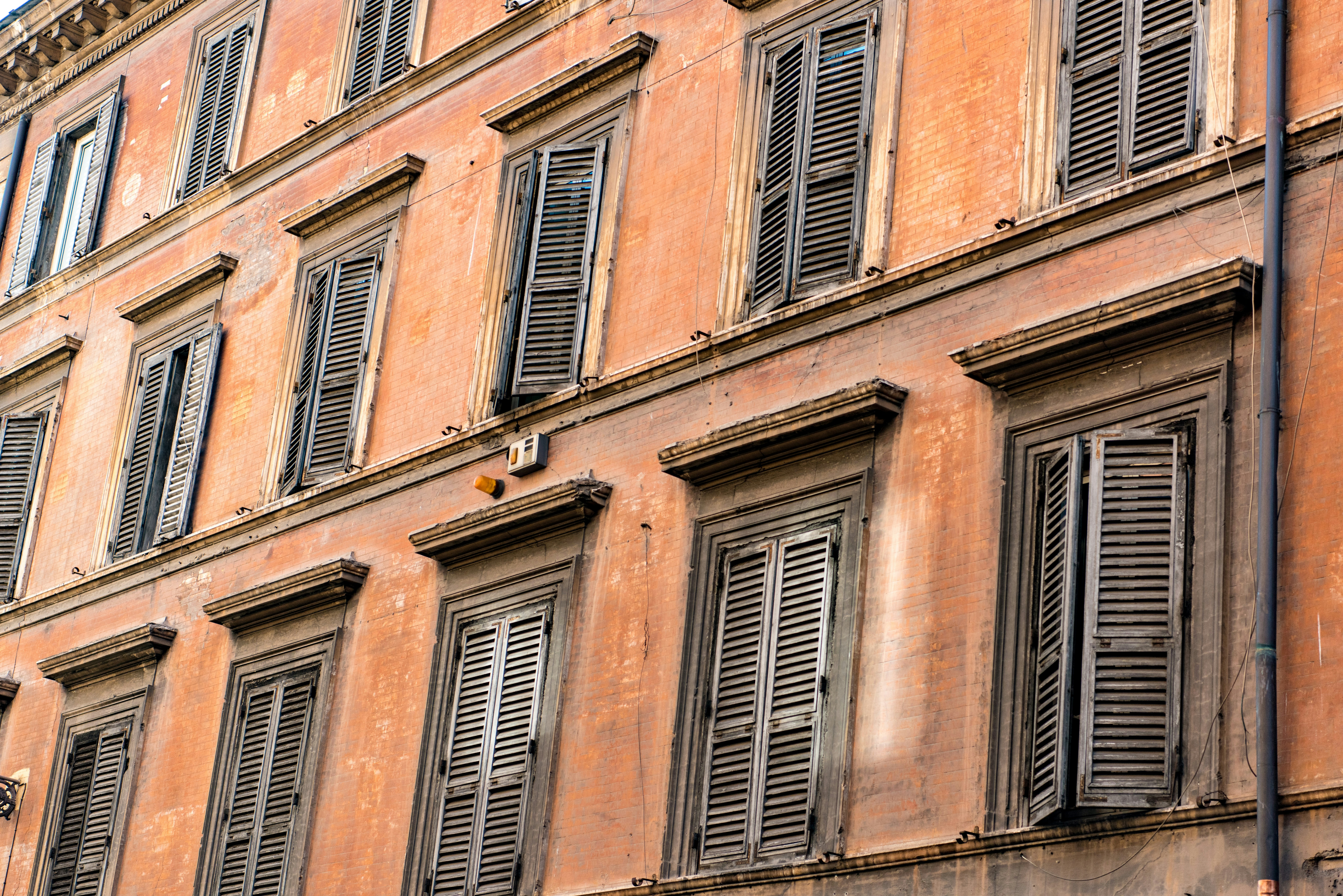 Weathered shutters on an aged building façade bask in warm sunlight.