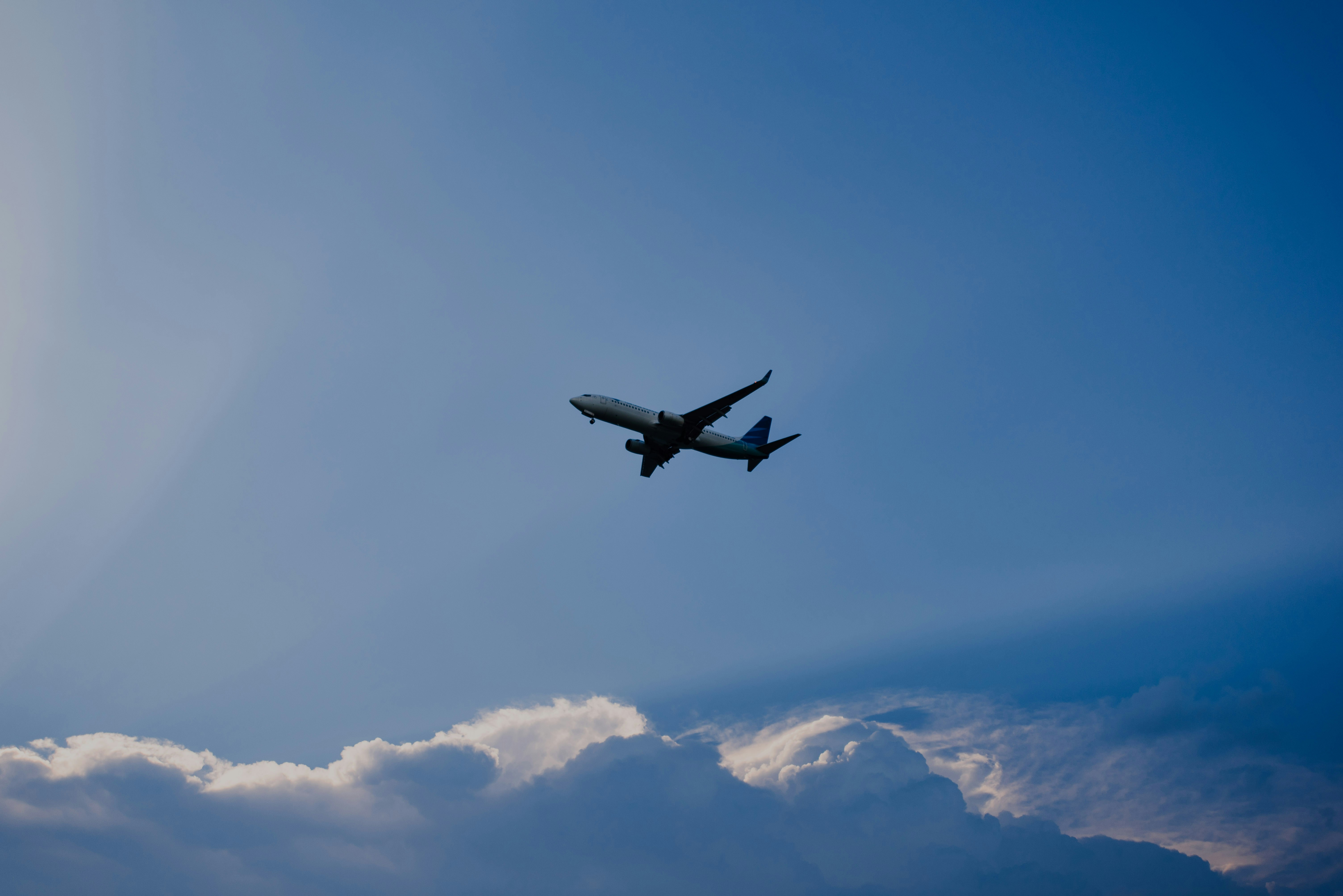 Commercial airplane gliding gracefully against a backdrop of blue sky and fluffy clouds.