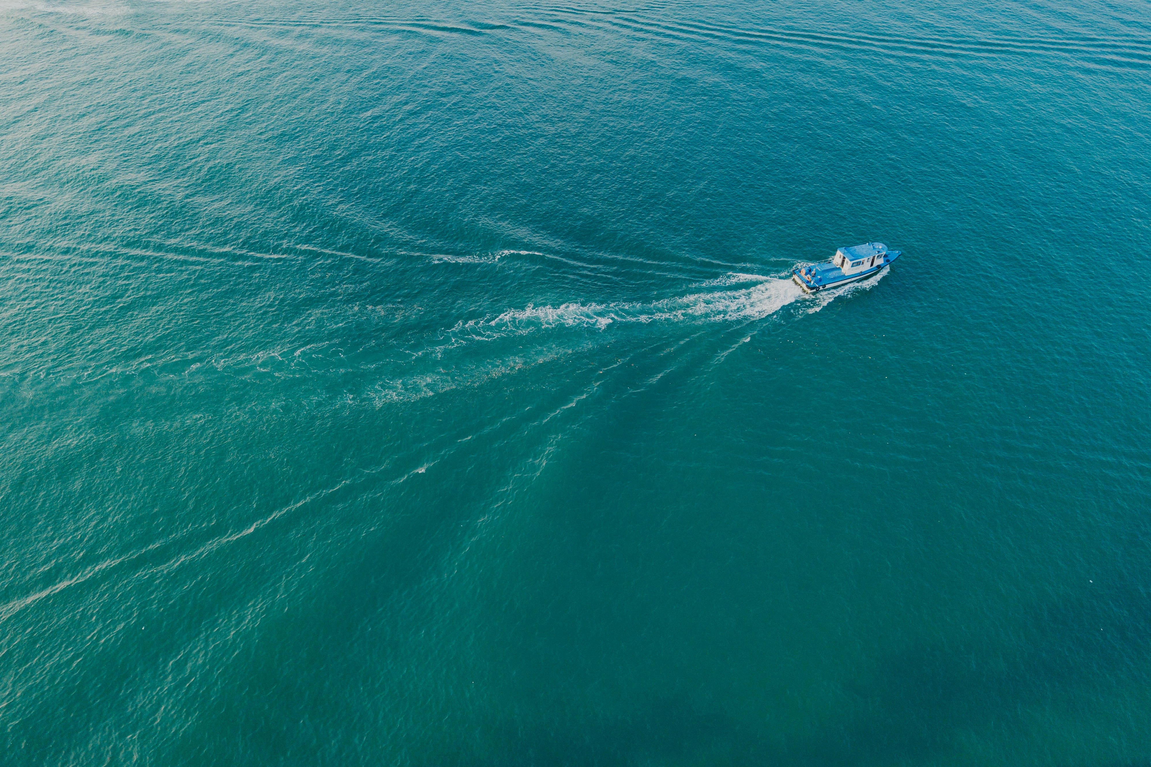 Boat leaving a white wake across vast blue-green sea.