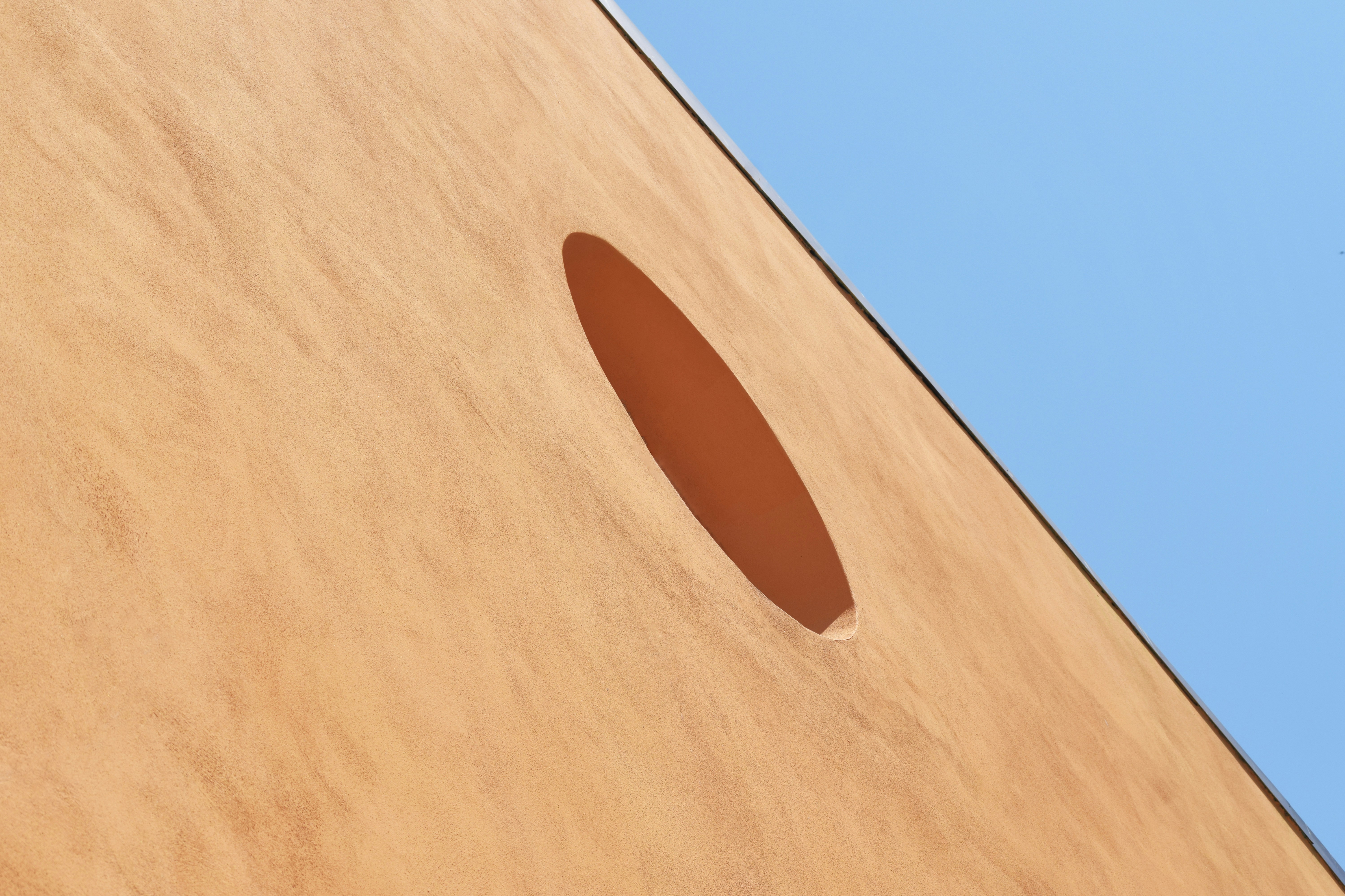 Ellipse Against a Sky: A Diagonal Wall’s Quiet Window
