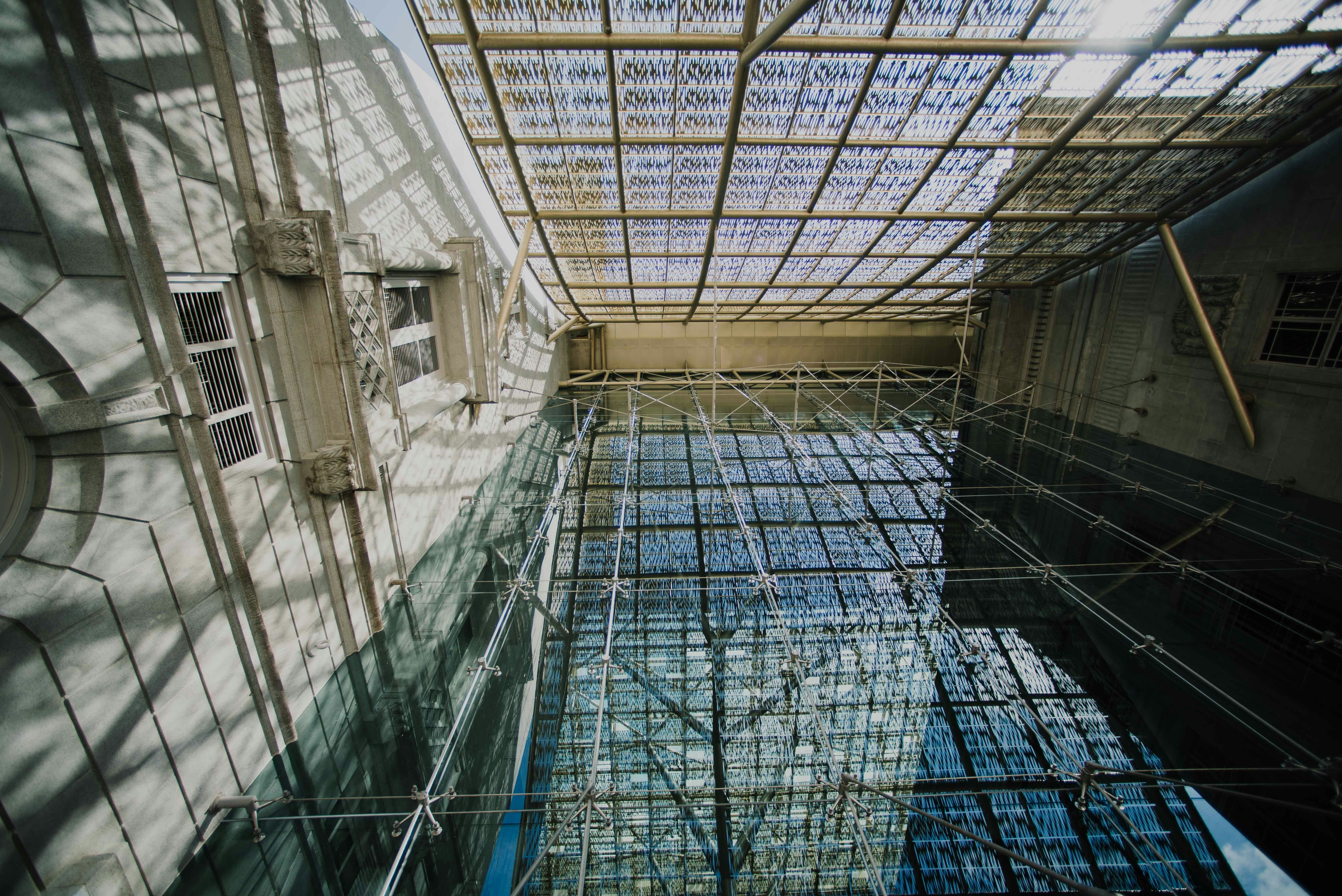 A unique perspective of a construction site with scaffolding and reflections on water, showcasing intricate patterns formed by light and shadow.