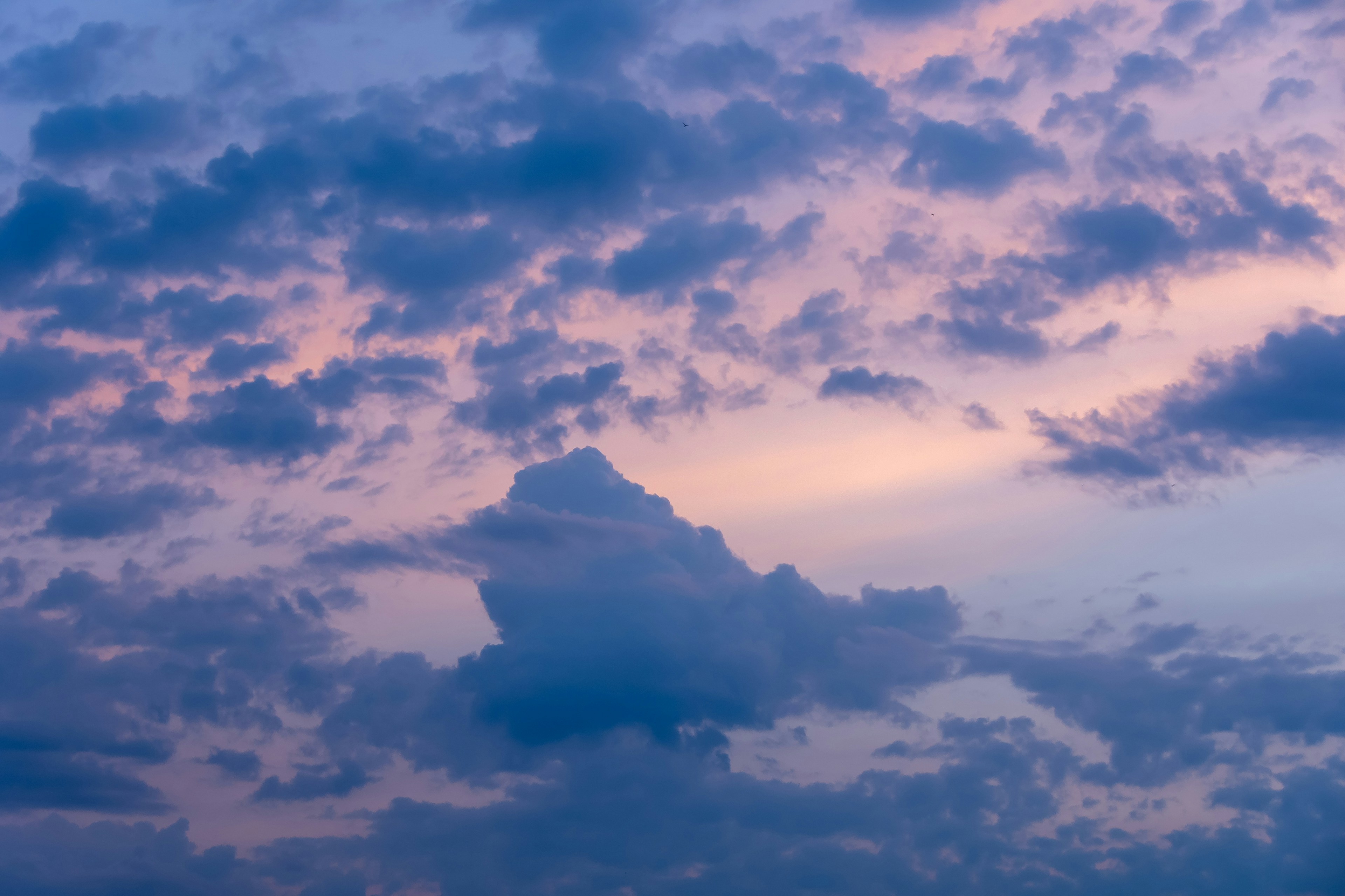 Soft pink and blue hues paint a dramatic sky filled with scattered clouds at dusk.
