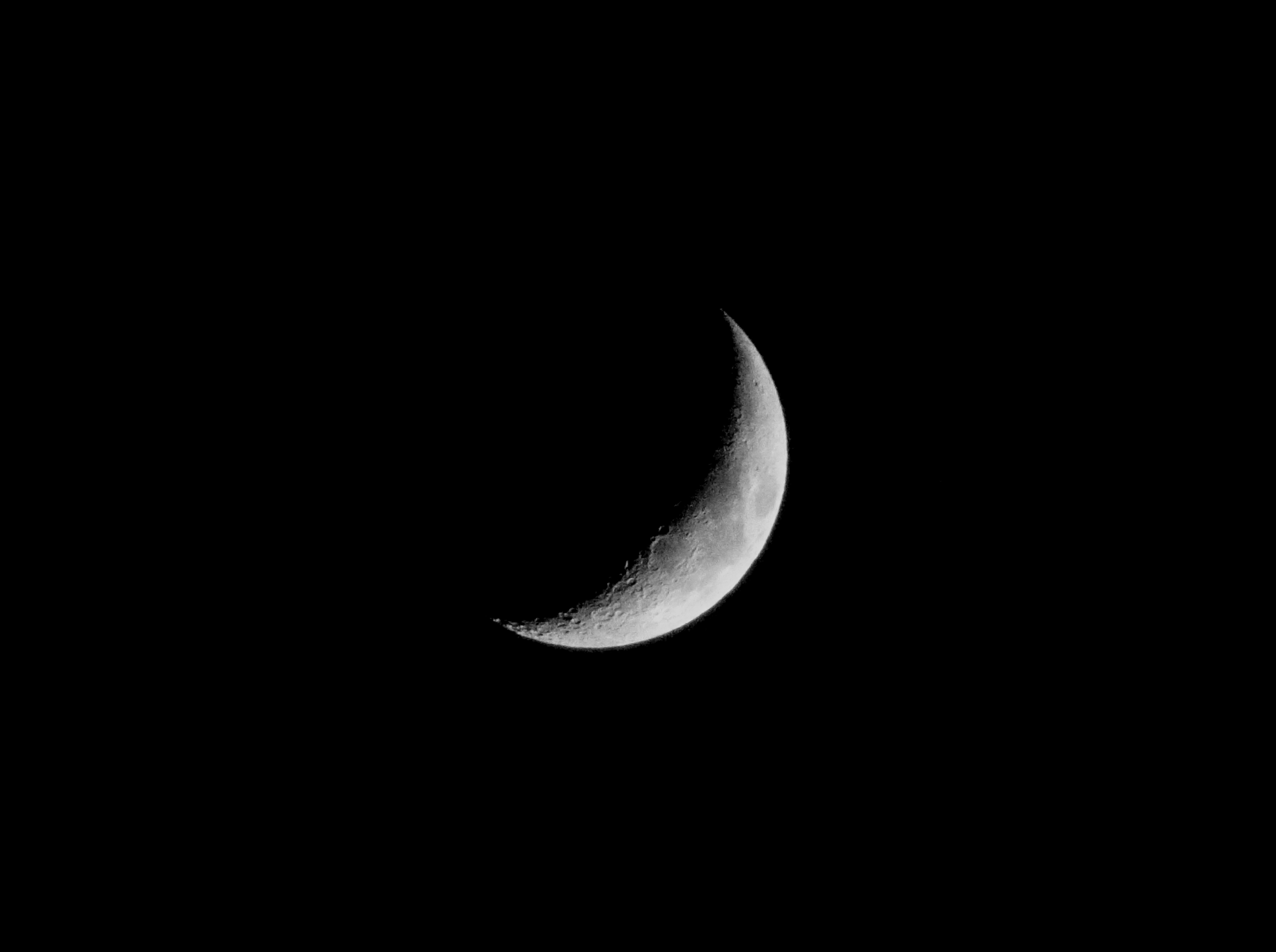 Crescent moon against a pitch-black night sky.