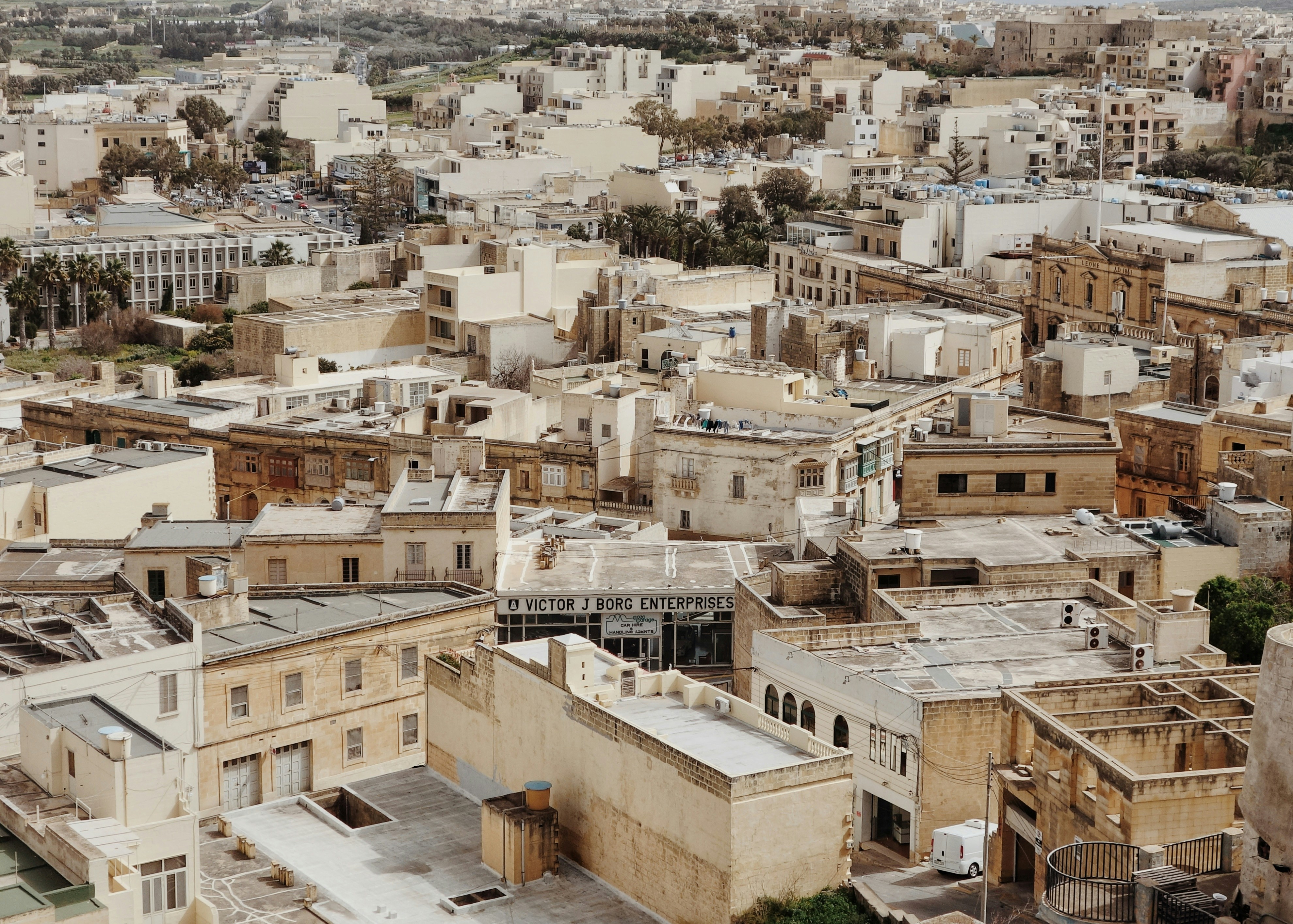 Aerial view of densely packed buildings in Malta, showcasing a blend of historical and modern architecture. The scene highlights the intricate layout and textures of the urban landscape.