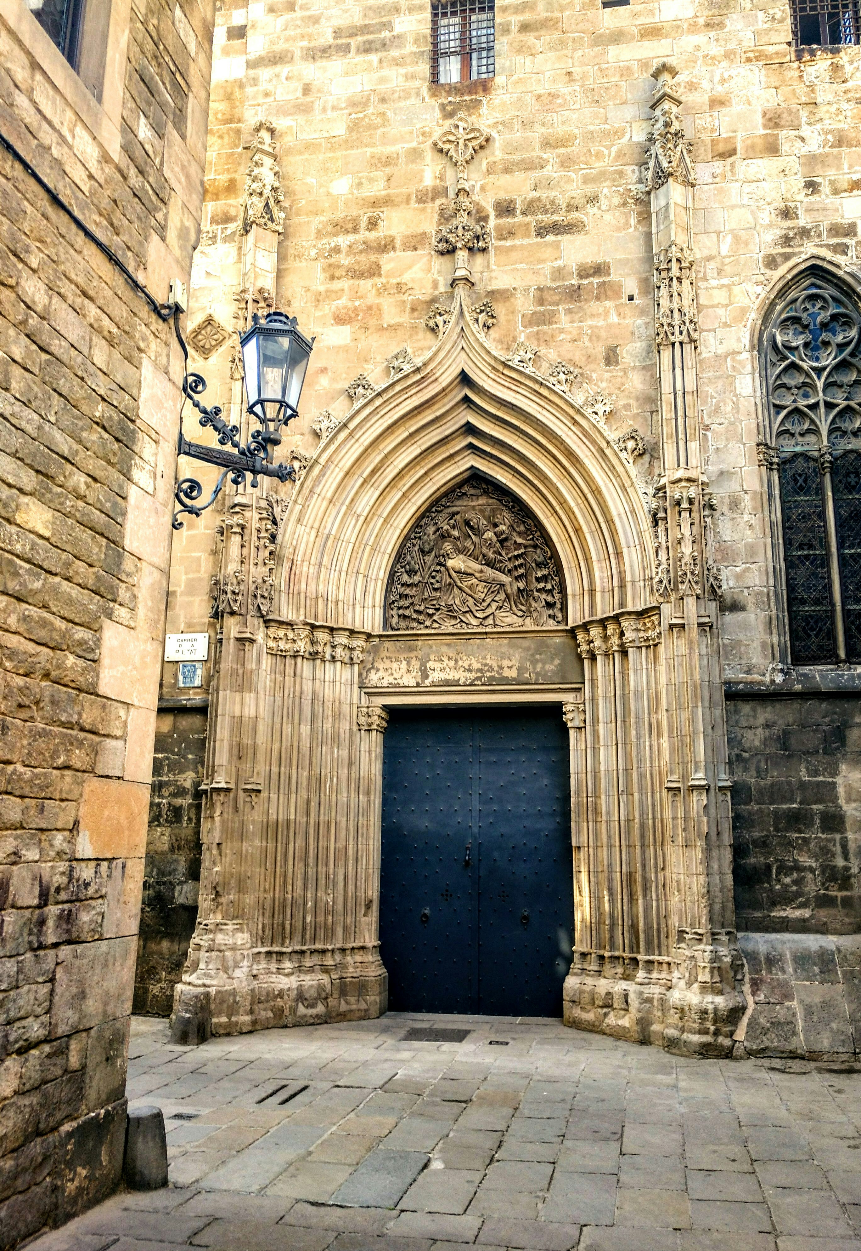 Gothic-style archway with intricate stone carvings and a large wooden door in a historic building.