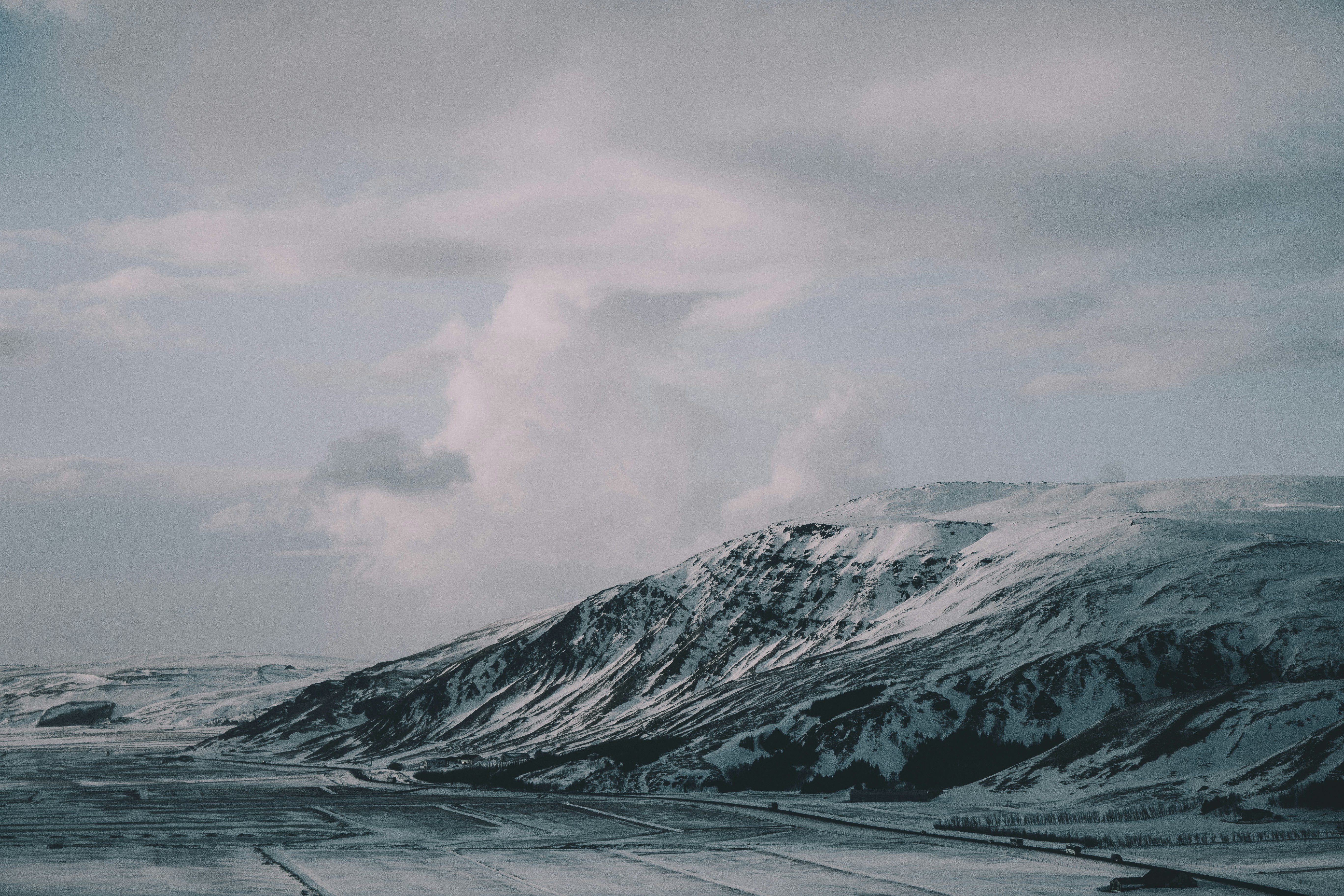 Snow-covered mountains under a cloudy sky, showcasing the serene beauty of a winter landscape.