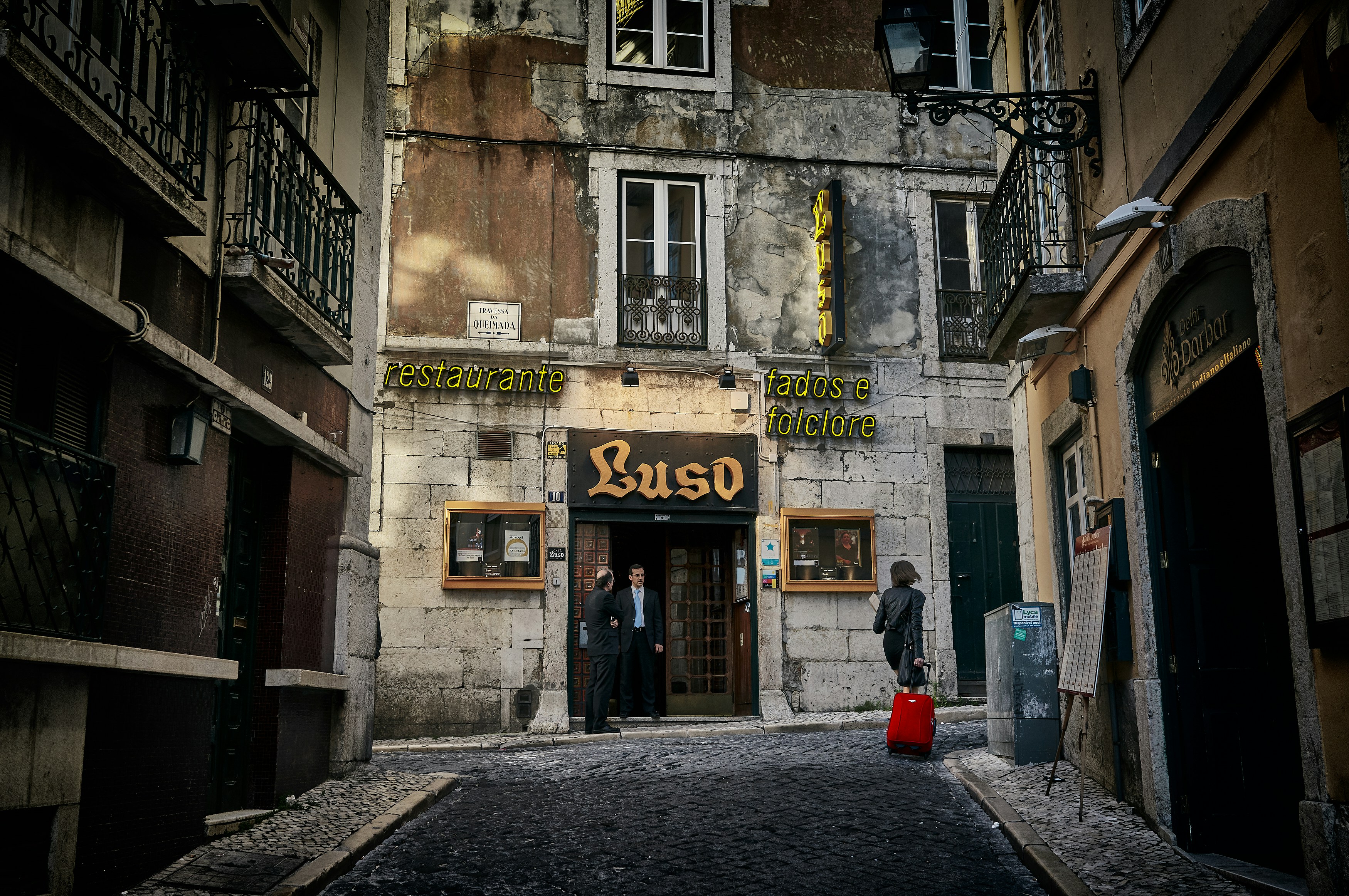 Lady with the Red Suitcase | two men standing outside Buso building