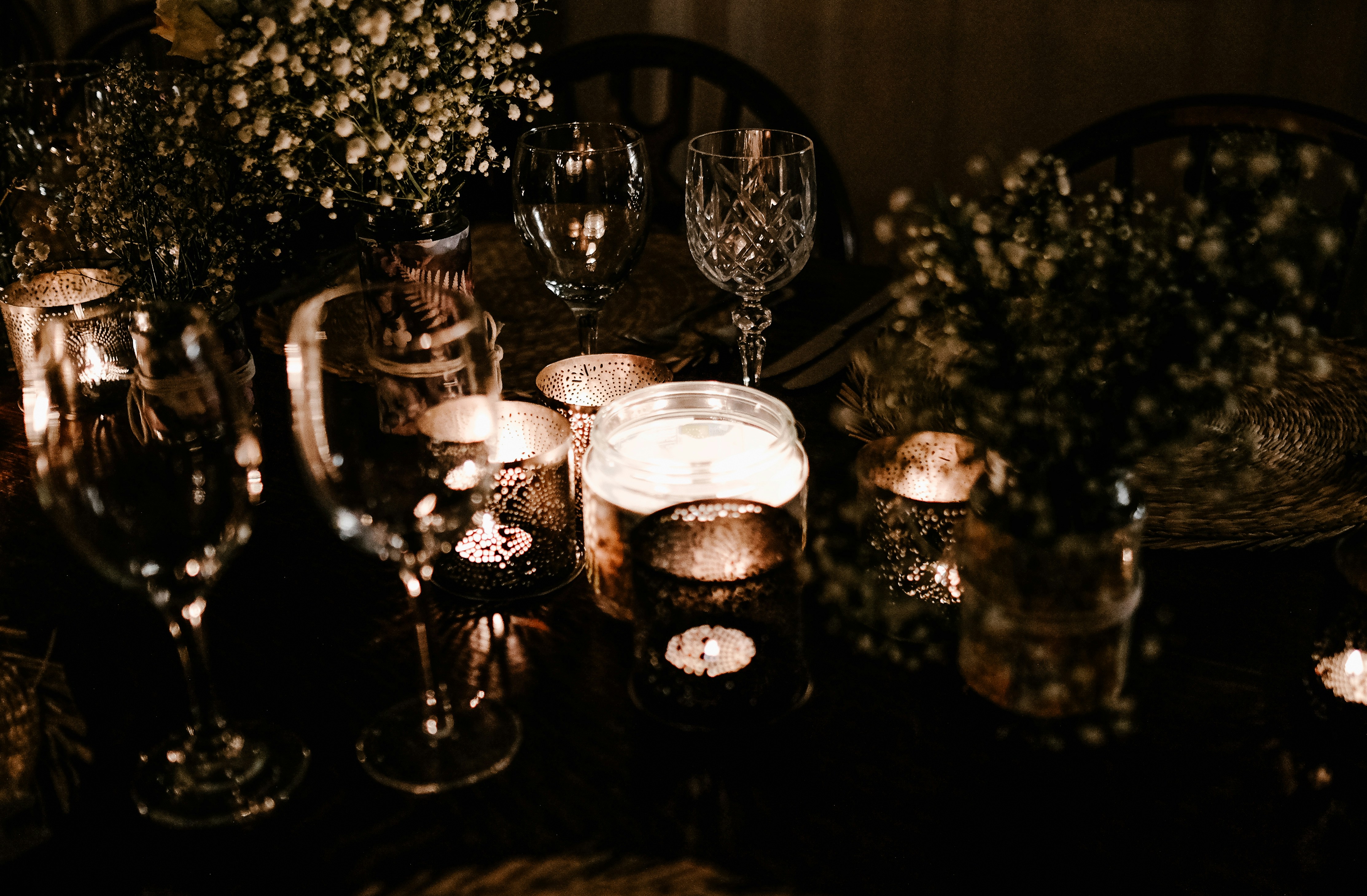 A beautifully set dining table adorned with delicate flowers and glowing candles, creating a warm and inviting atmosphere for an intimate gathering.