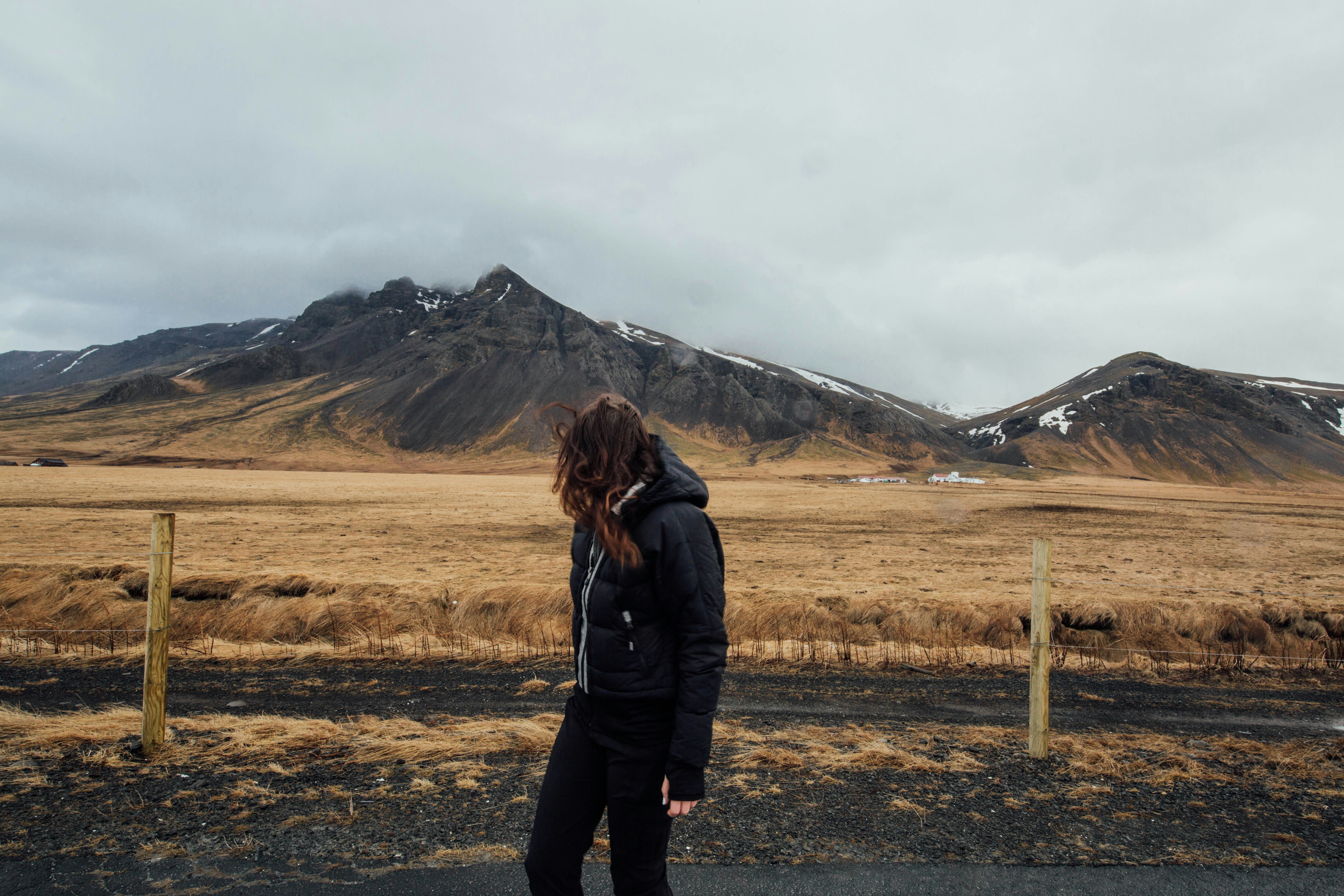 Lone wanderer on a windswept plateau beneath rugged Icelandic peaks