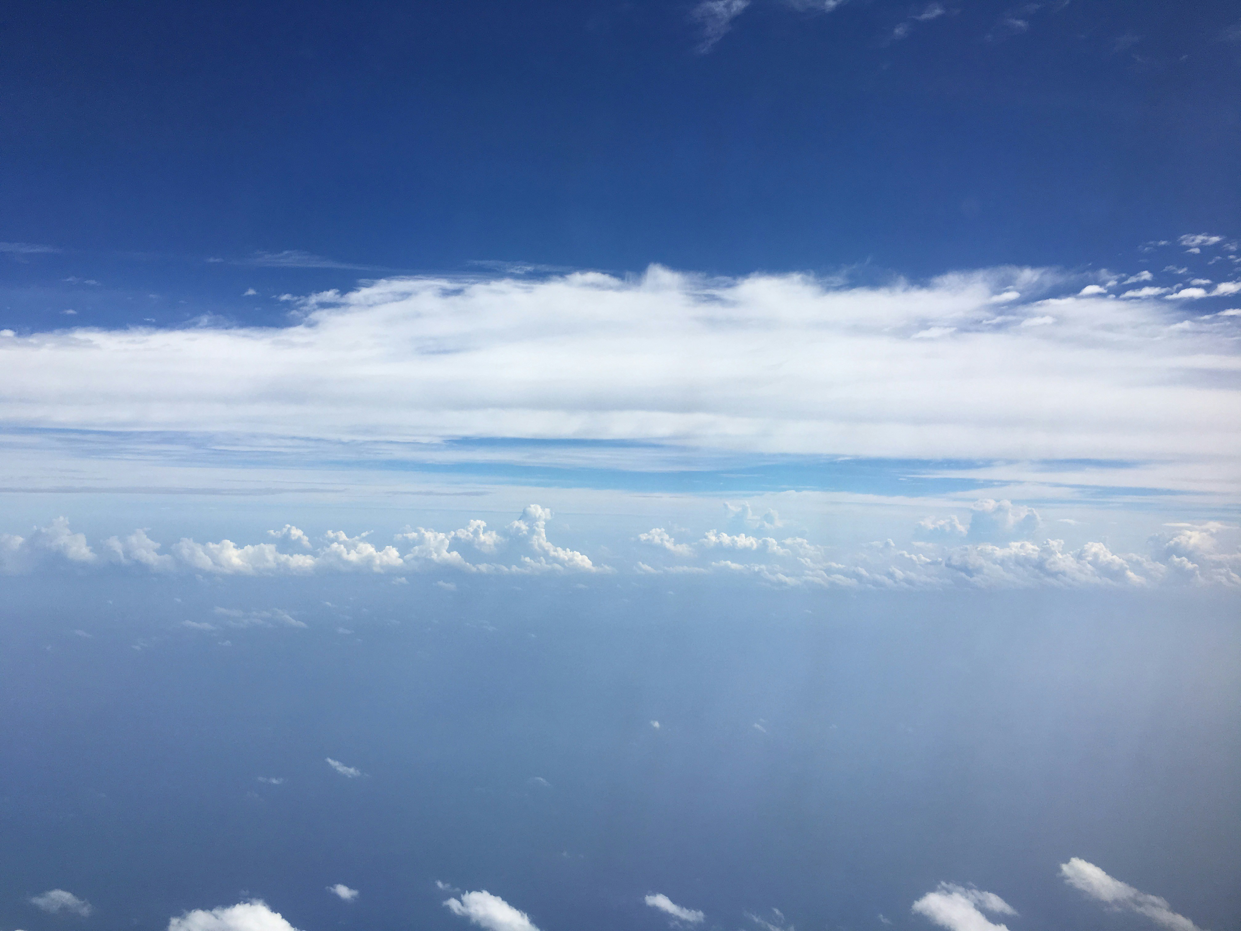 Vast expanse of blue sky with scattered clouds, viewed from above. The serene atmosphere evokes a sense of tranquility.