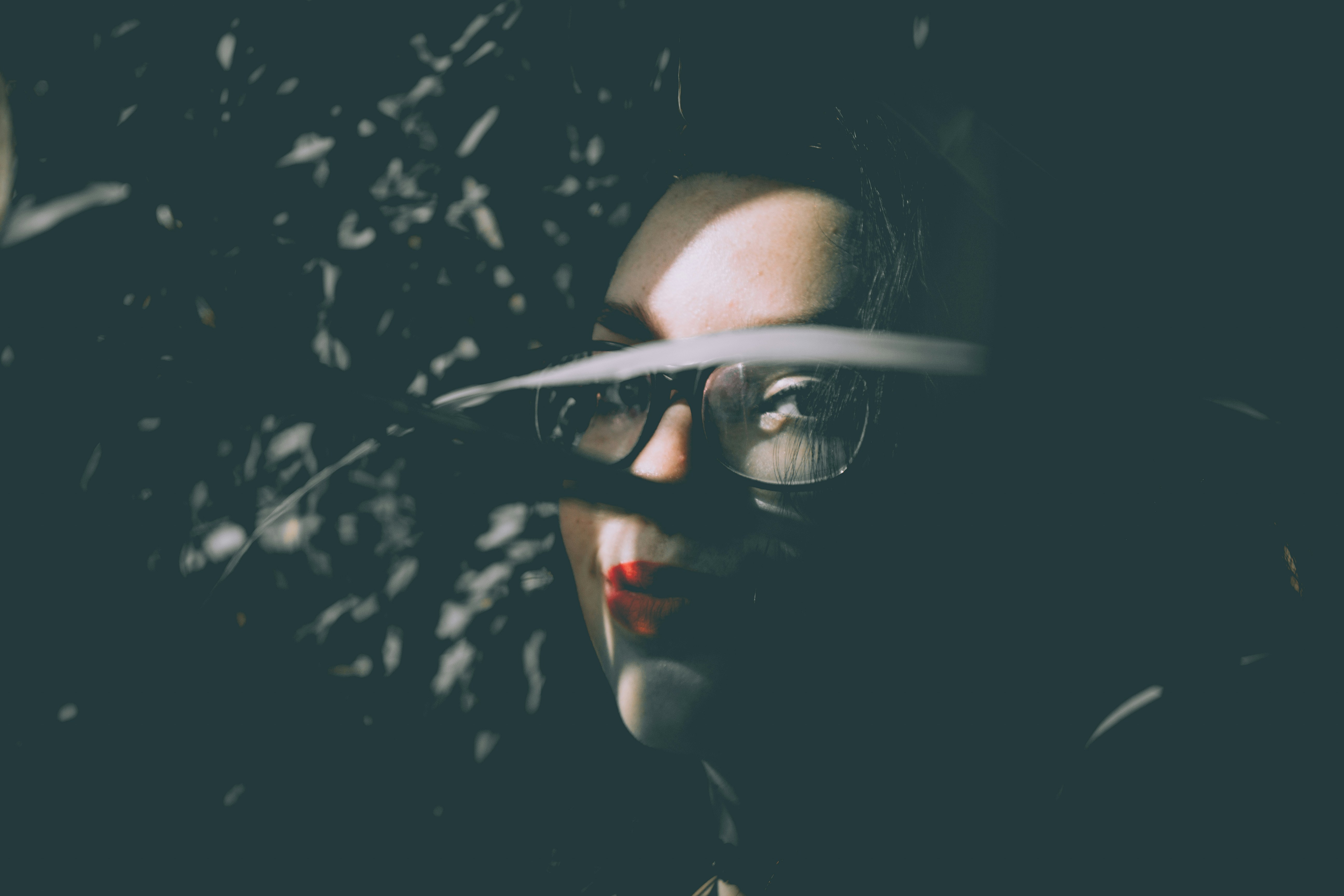 Shadowed Glance Portrait: Low-Light Mood with Glare Across Glasses