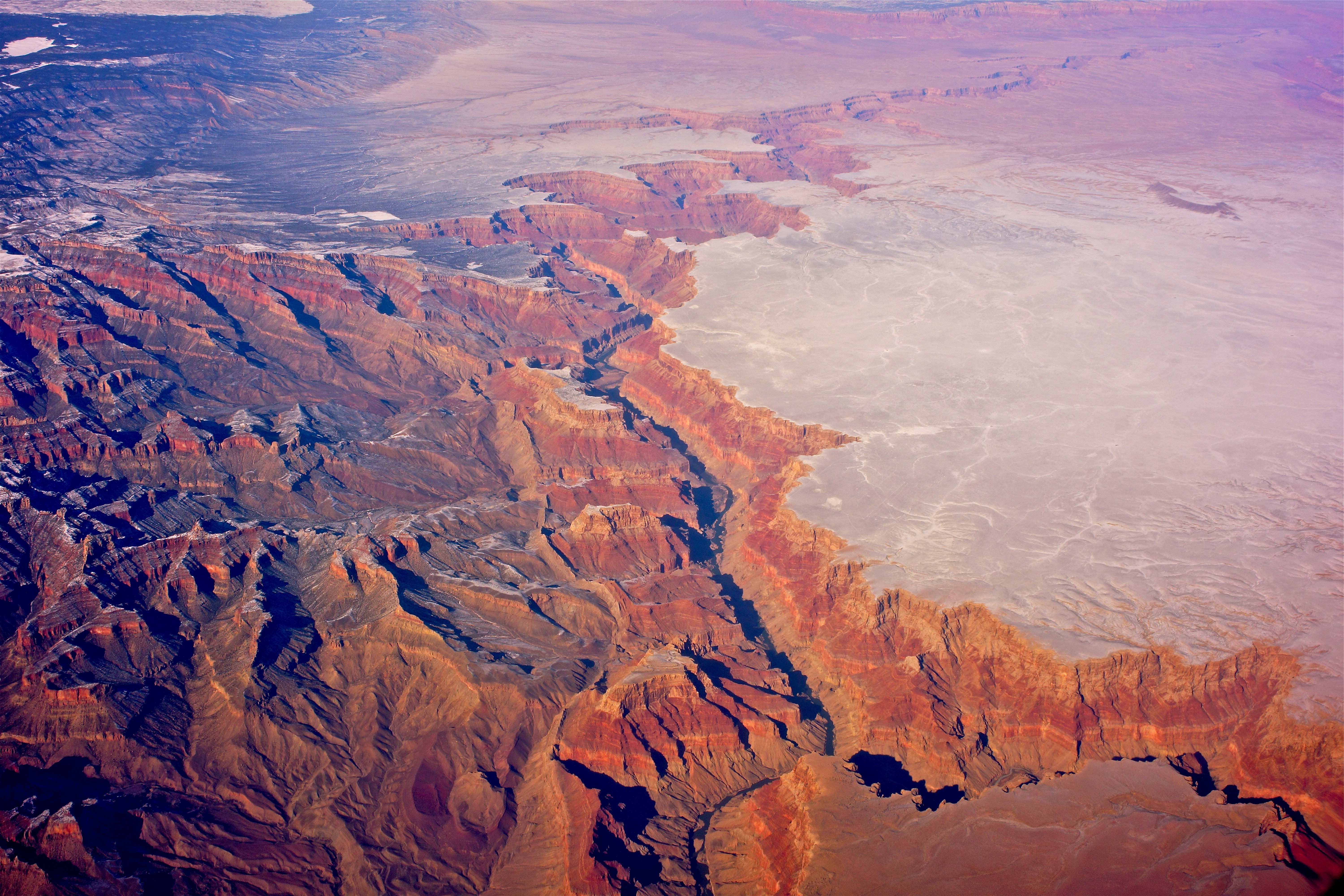 Aerial view of the Grand Canyon showcasing its intricate layers and vast expanse under a warm light.