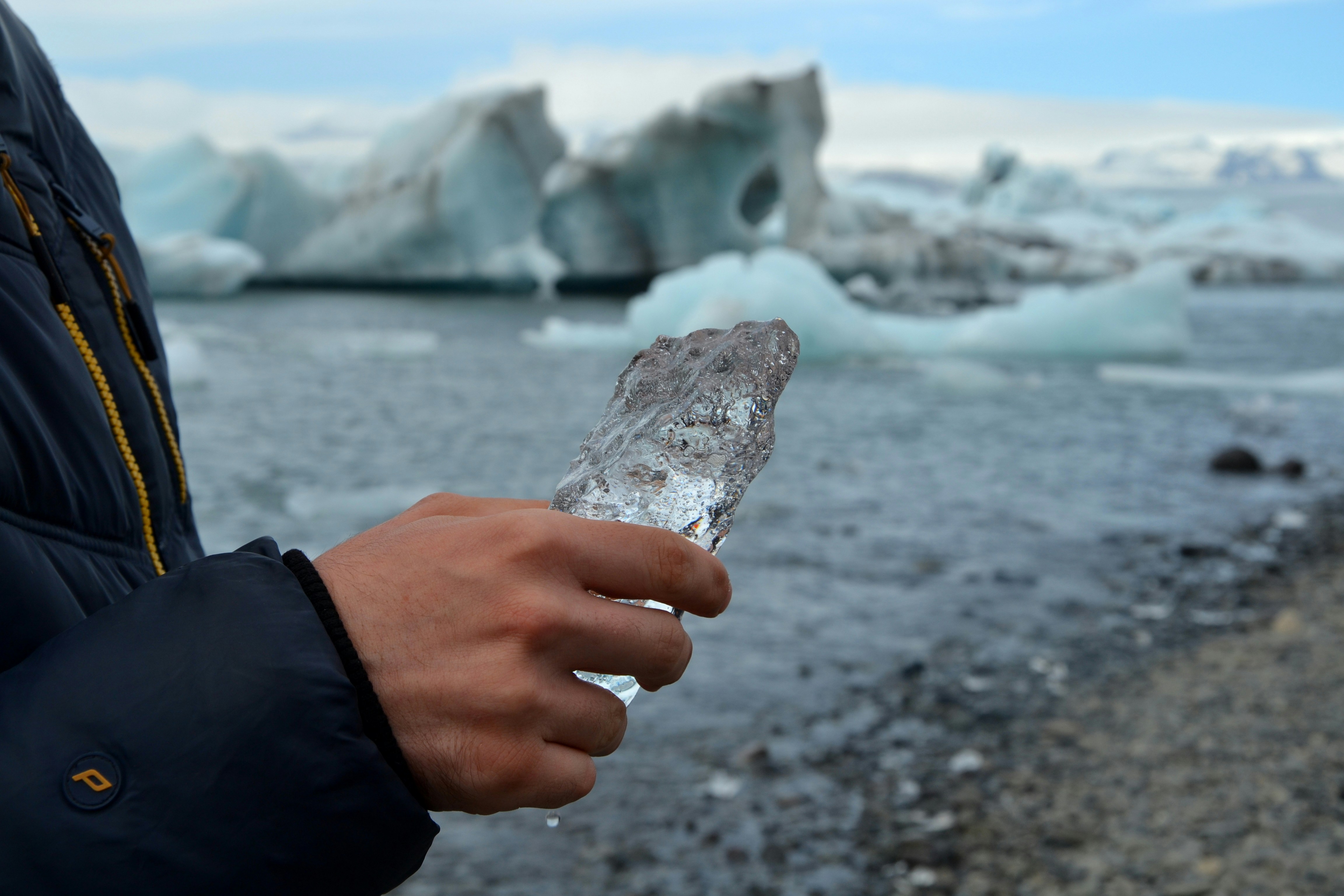 Crystal Fragment in Focus: A Handful of Ice Before a Glacier Seascape