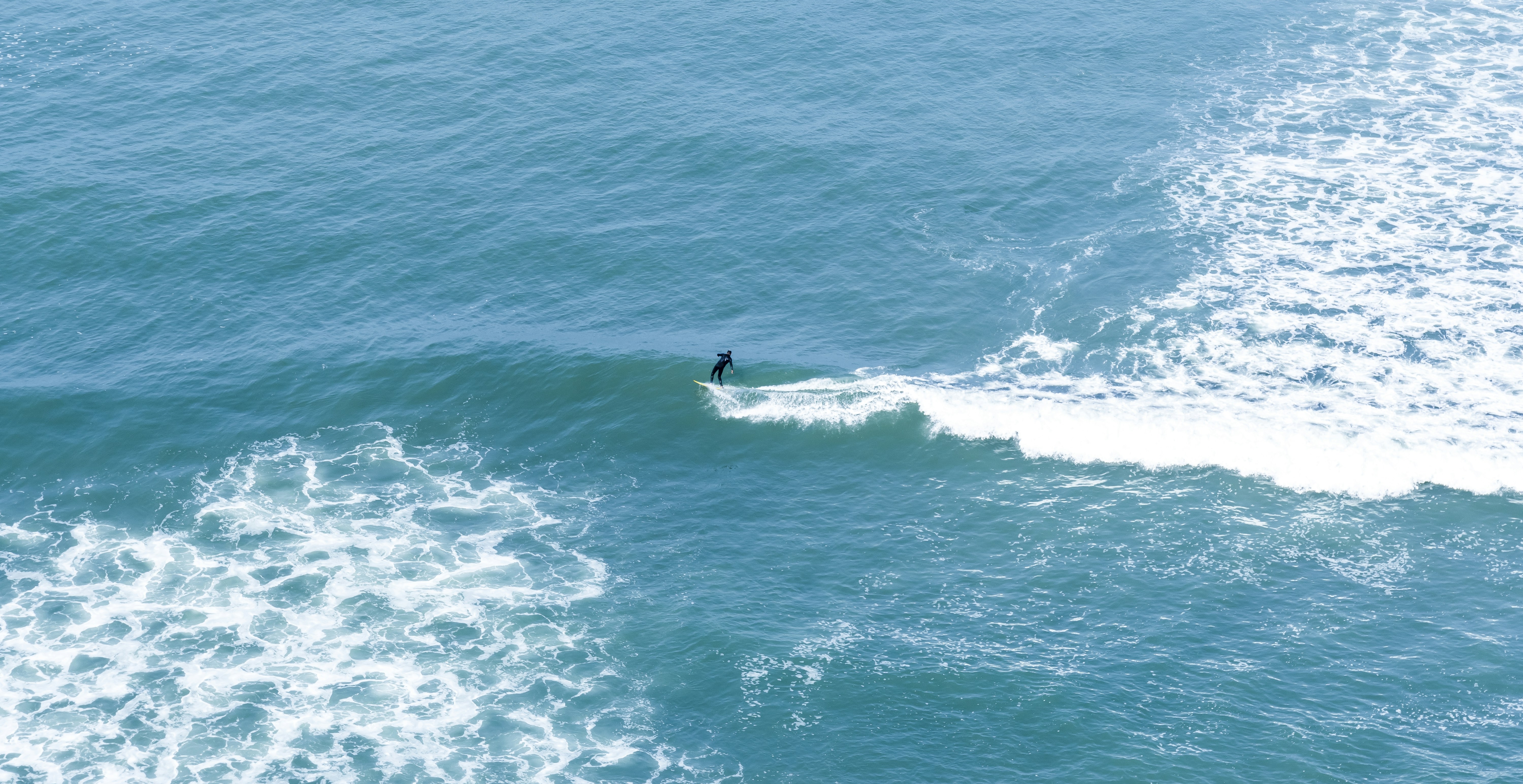 Surfer skillfully navigating a wave under a clear blue sky, showcasing the thrill of ocean sports.