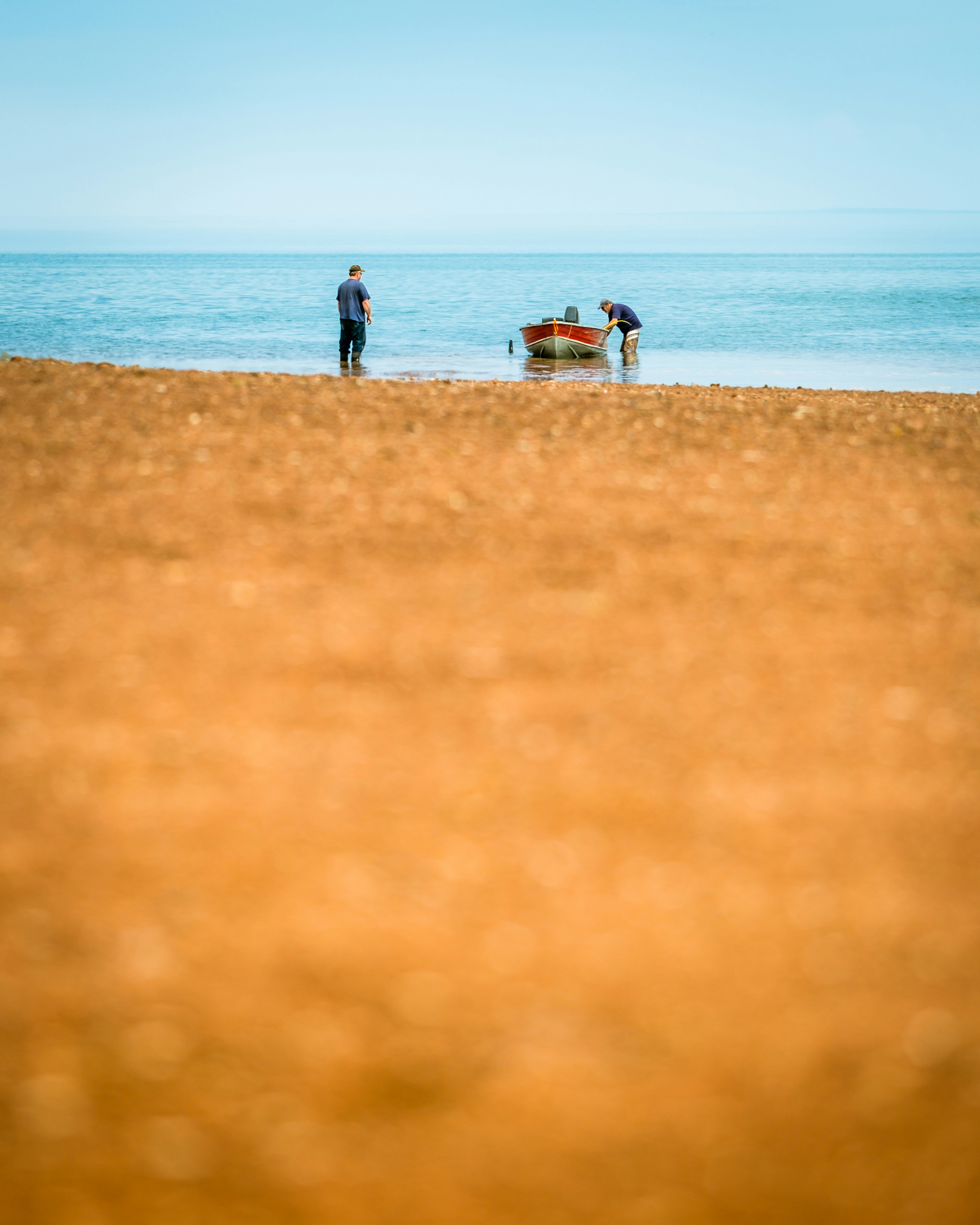 Two man in body of water beside boat photo – Free Orange Image on Unsplash