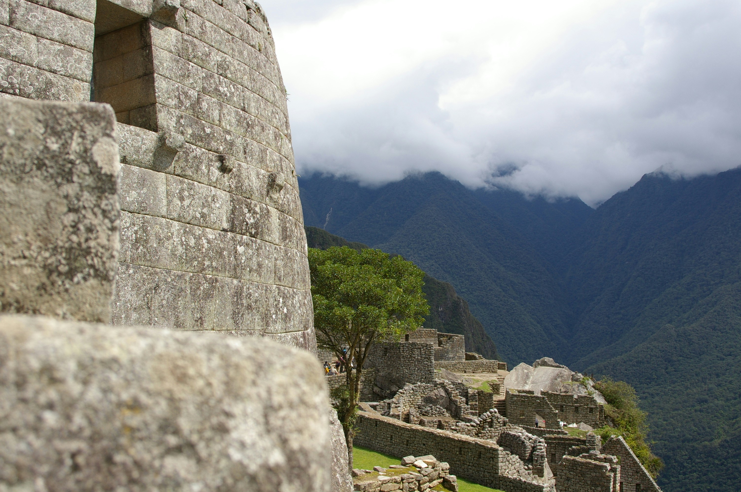 Ancient stone structures of Machu Picchu nestled against a backdrop of majestic mountains and clouds. The scene evokes a sense of history and mystery.