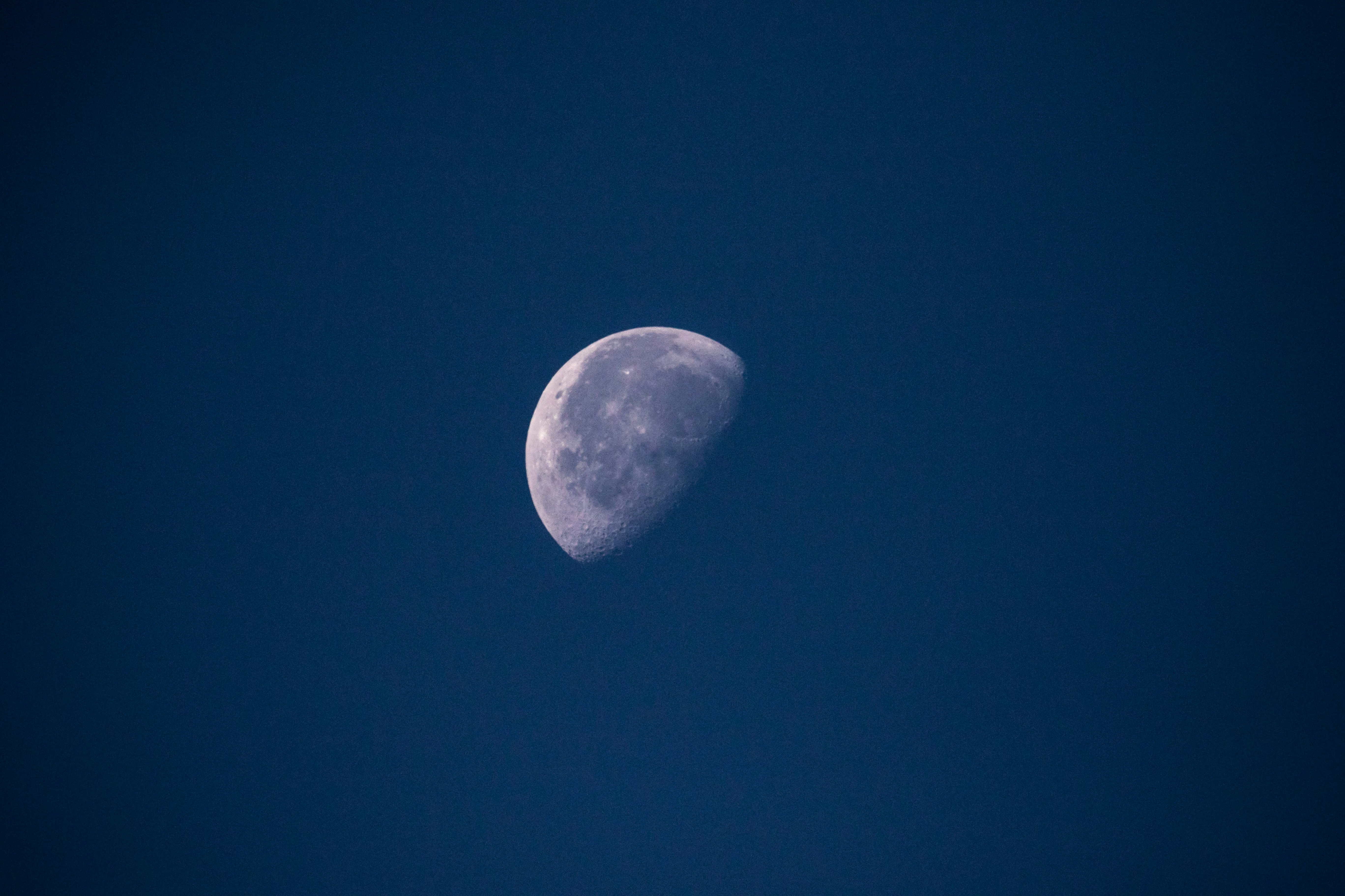 Waxing gibbous moon against a deep blue sky, showcasing its craters and surface details.