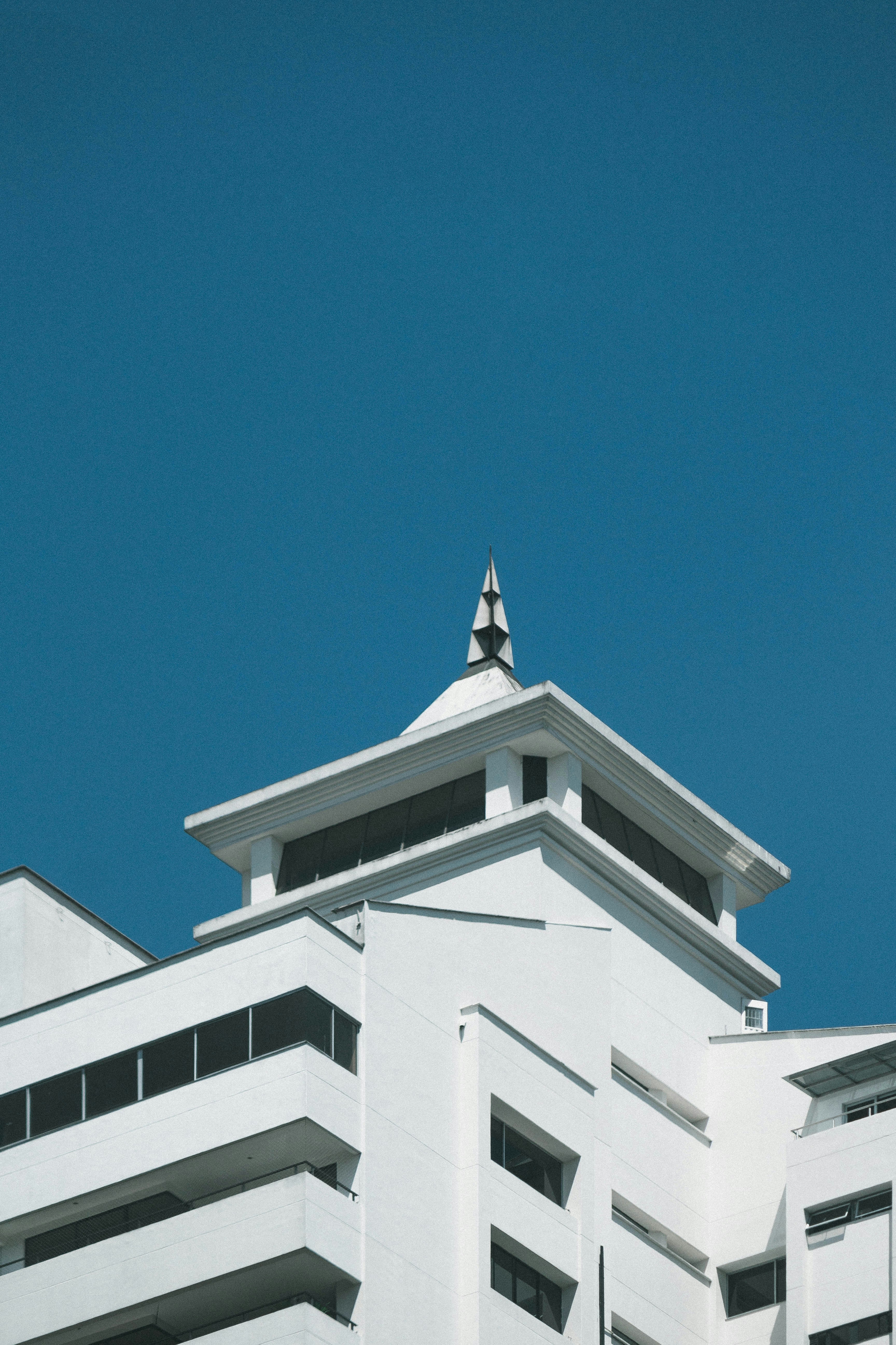 White modern building with a distinctive pointed roof against a clear blue sky.