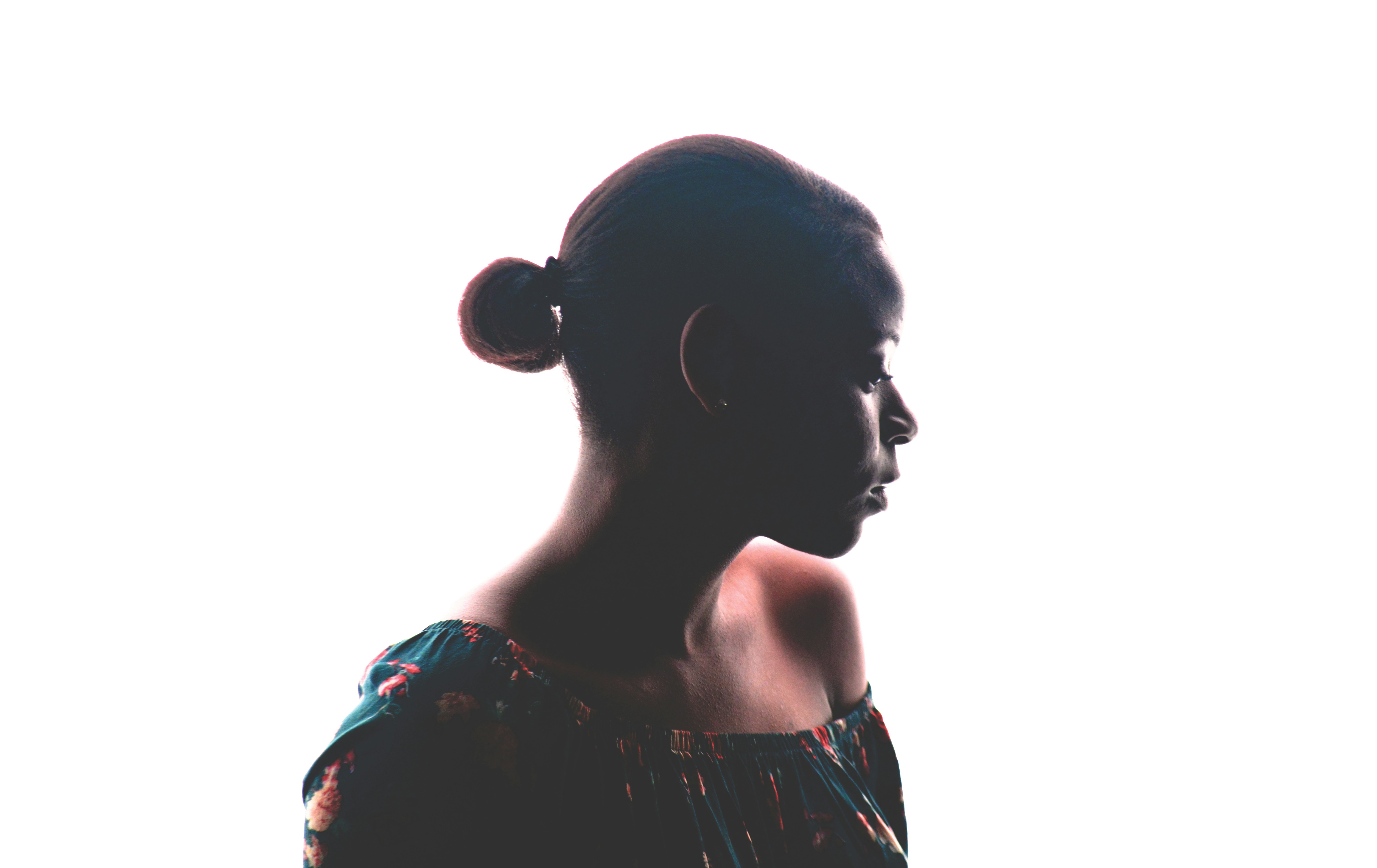 Silhouette of a woman with hair in a bun against a stark white background.